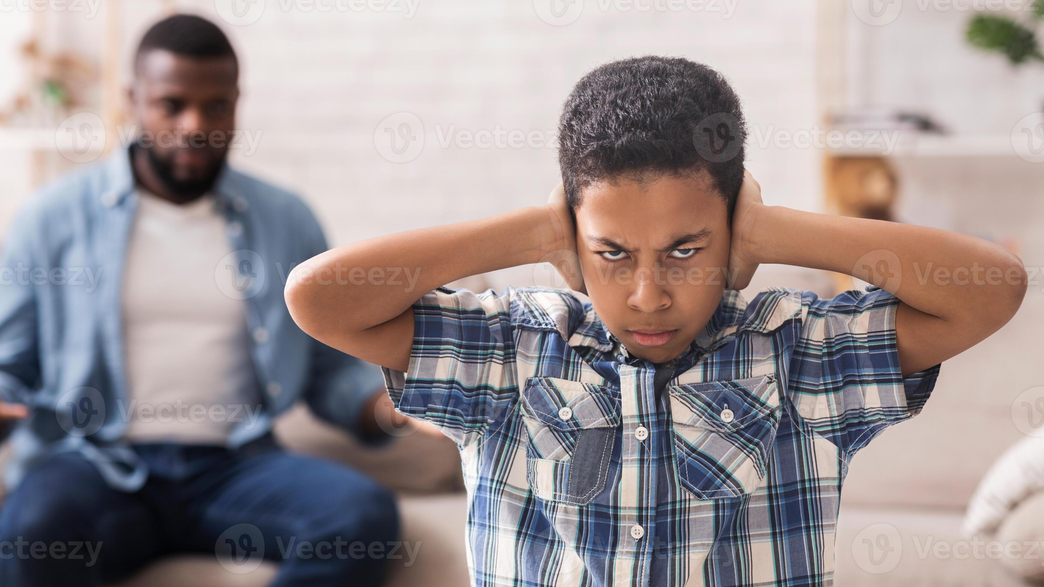 Disobedient Child. Preteen black boy closing ears not to listen father's scolding after his bad ...