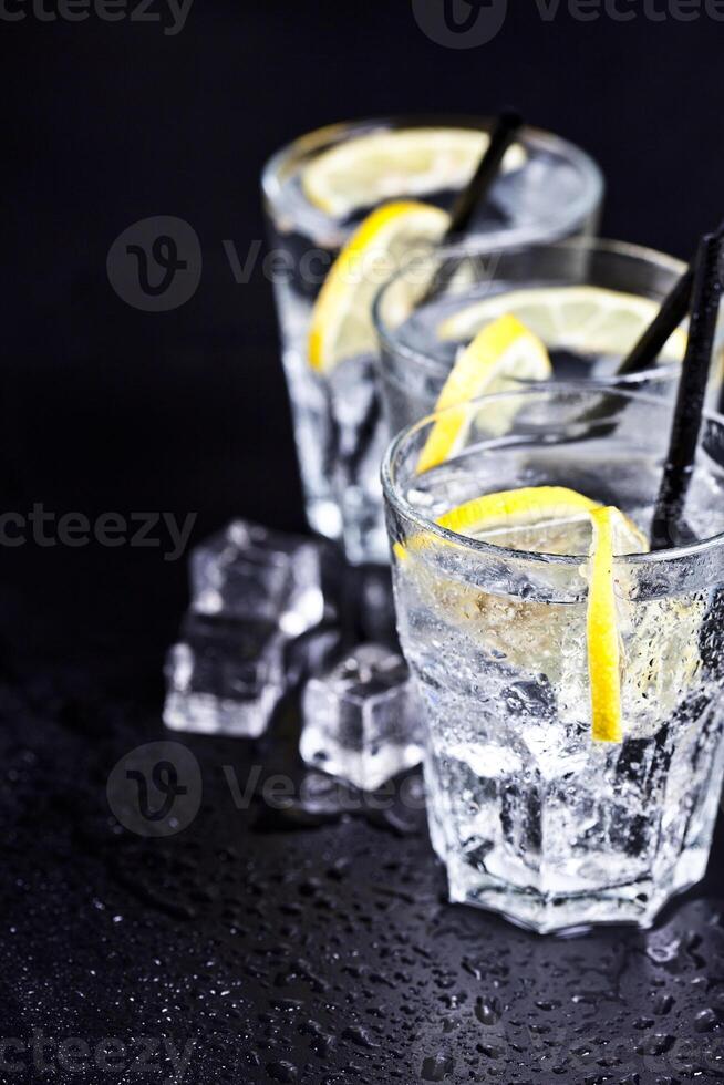 Three glasses with fresh cold carbonated water with lemon slices and ice cubes closeup. 52039322 ...