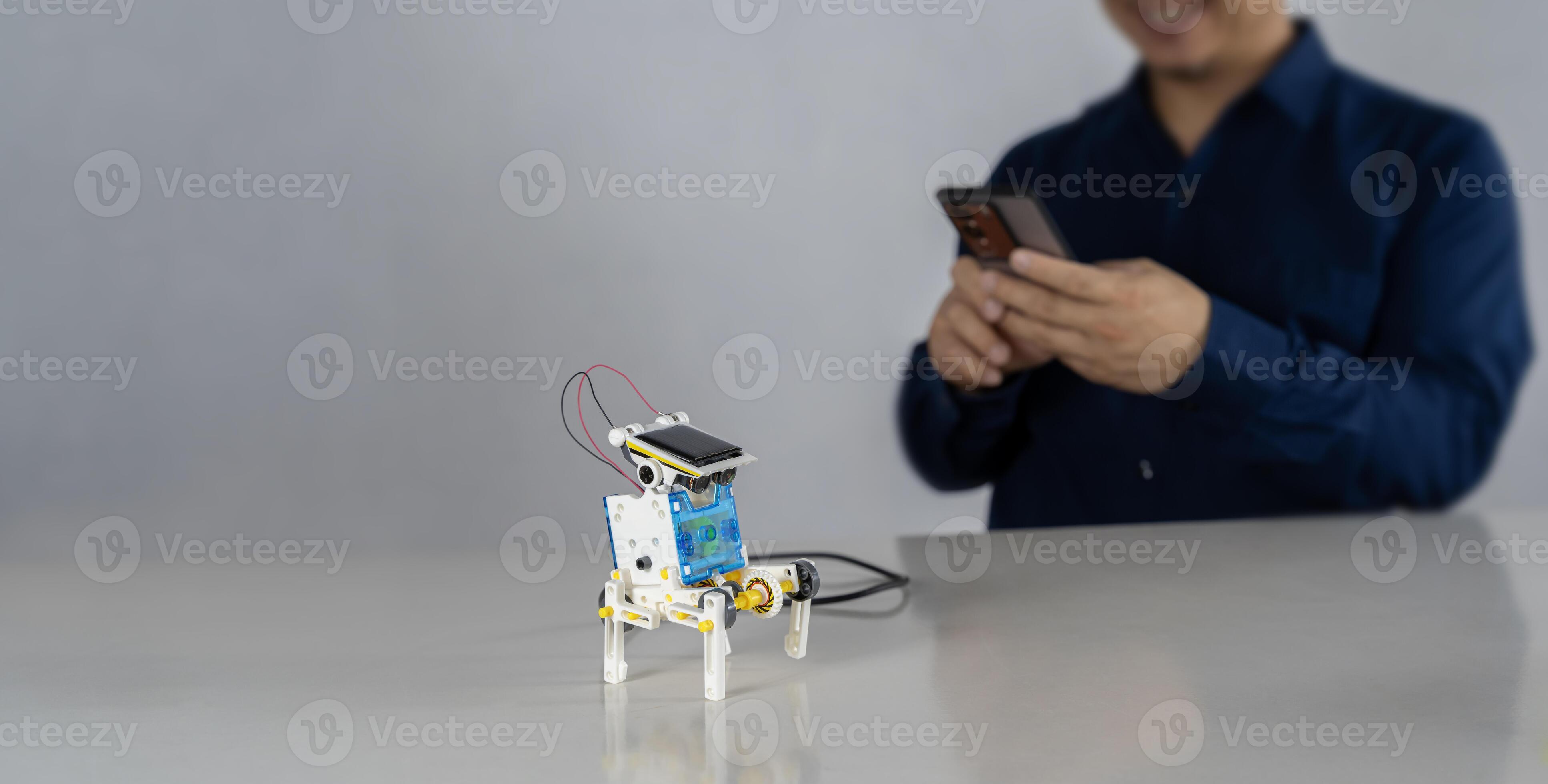 Young attractive students of mechatronics working on project. A plastic robot is in the hand of ...