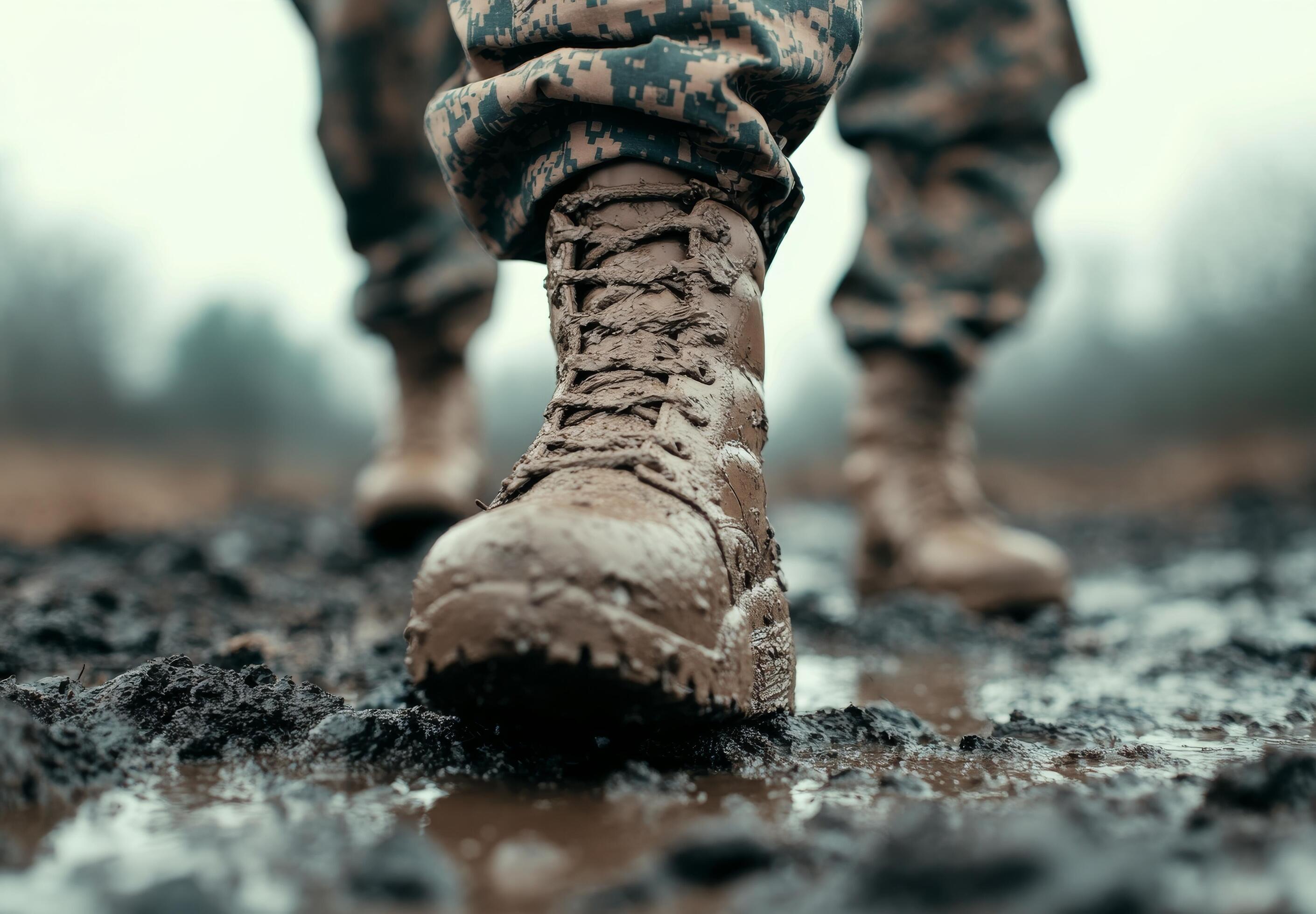 Soldiers in the rain preparing for training in a muddy environment with focus on combat boots ...