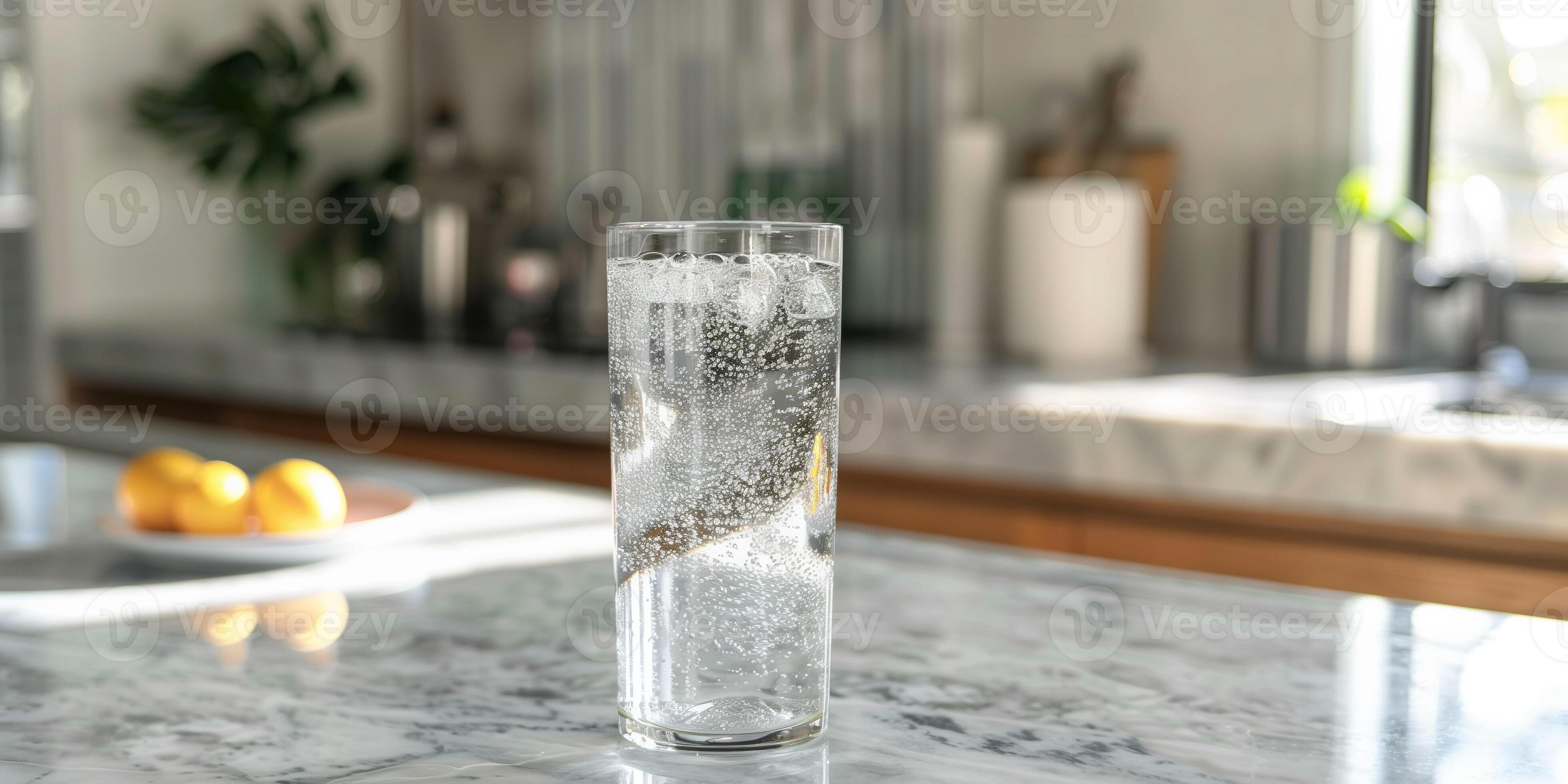 Transparent glass filled with clear sparkling water and bubbles rising, placed on a marble ...