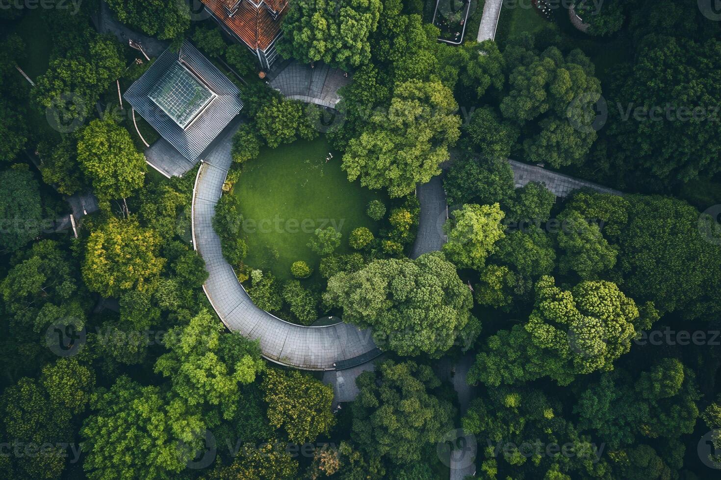 Aerial view of a curved pathway winding through lush green foliage and a central lawn. 53424071 ...