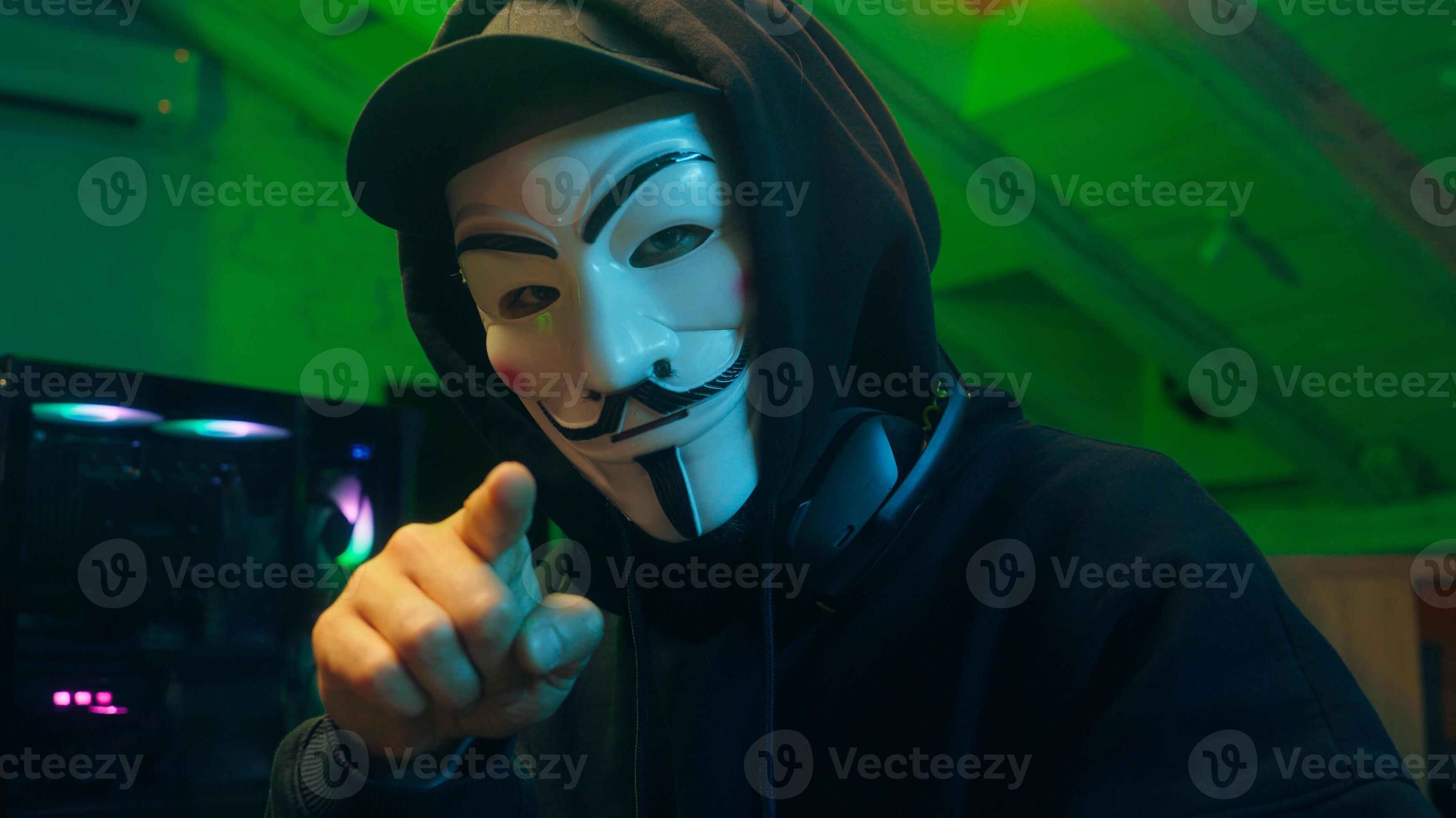 Lviv, Ukraine - June 03, 2024. Hacker anonymous typing computer looking at camera pointing ...