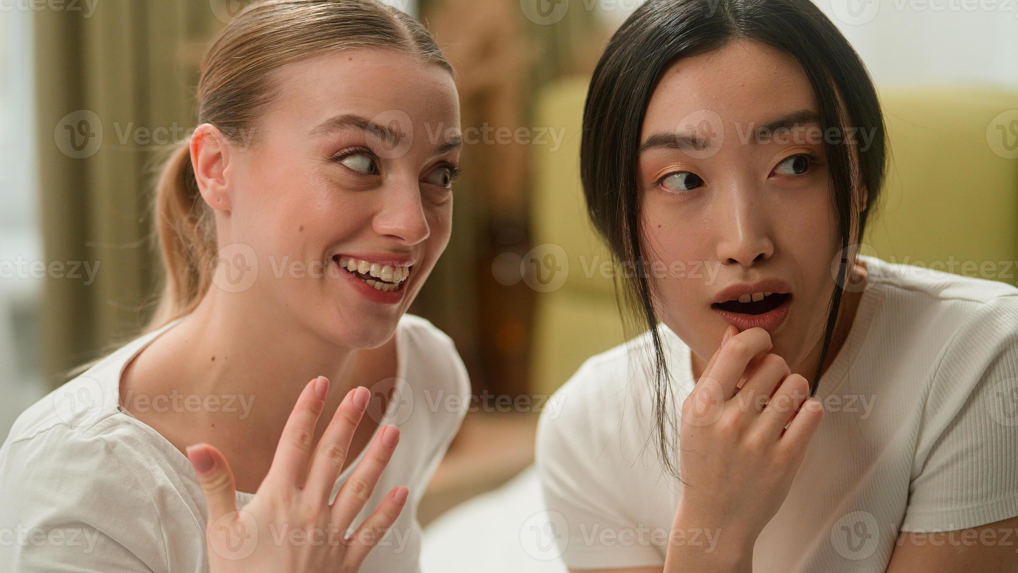 Multiracial friends women Caucasian woman whisper secret gossip talk secrecy information on ear ...