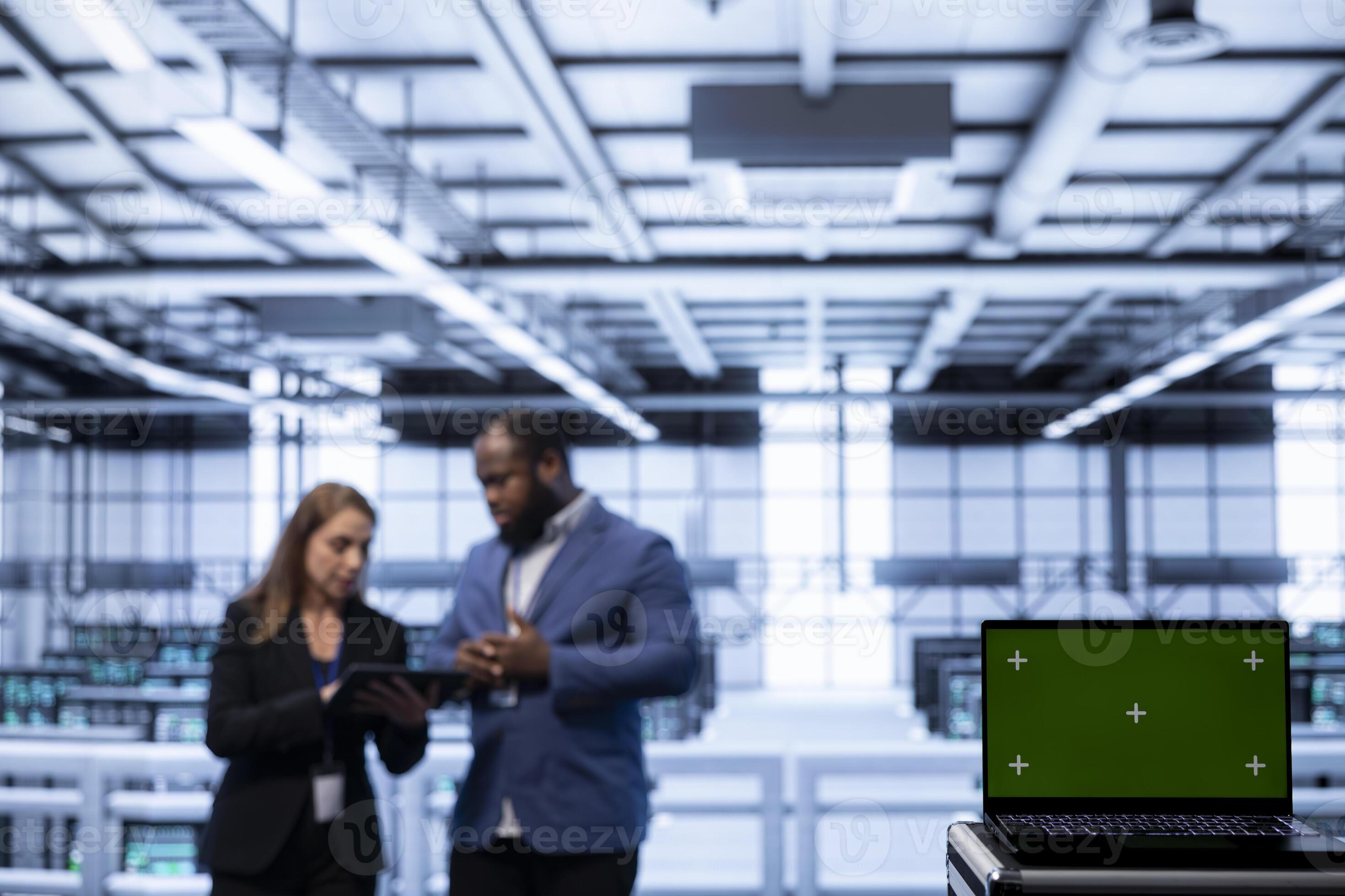 Focus on mockup laptop used by coworkers in data center ensuring cybersecurity and efficient ...