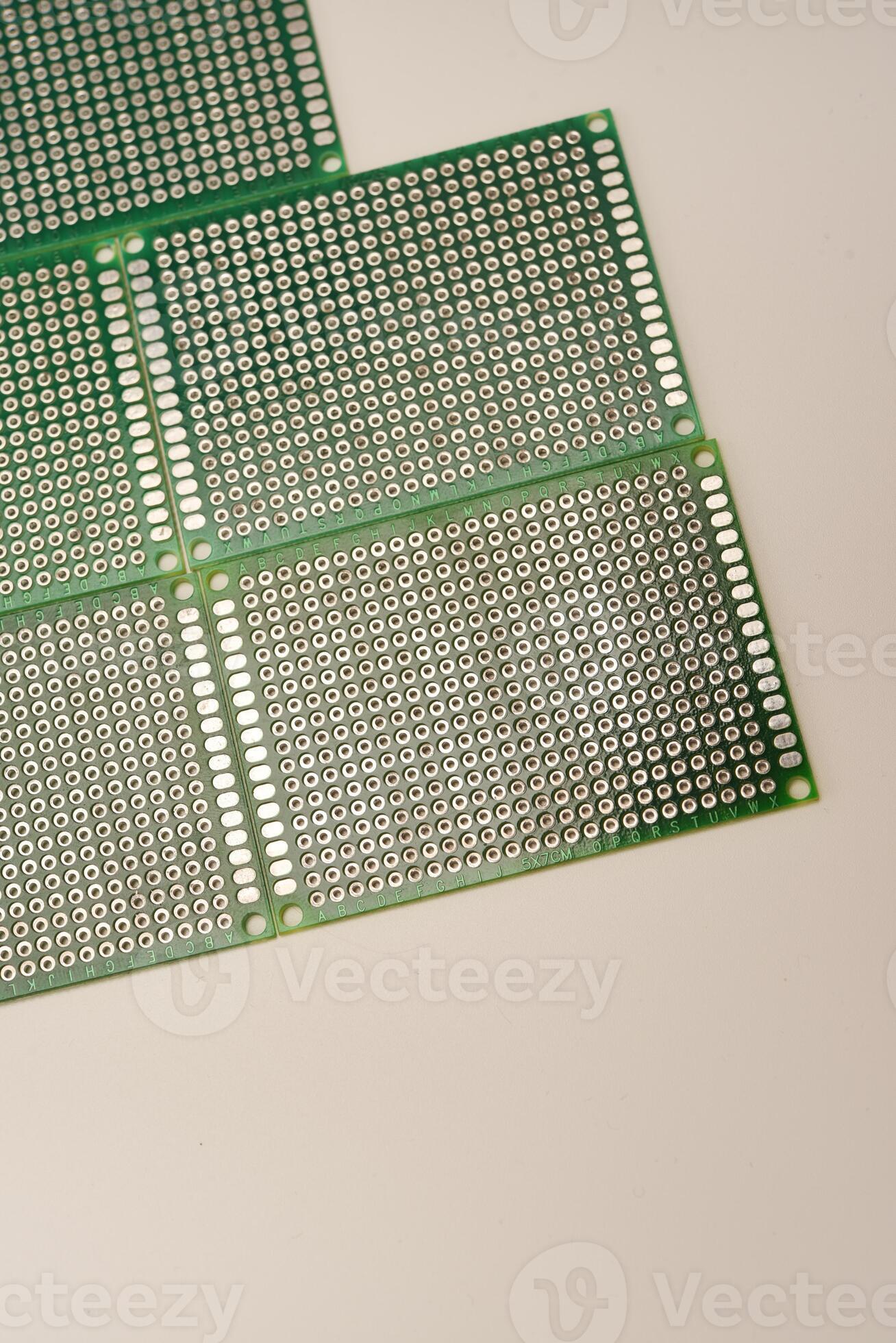 A green breadboard for electronics on a white background. Printed ...
