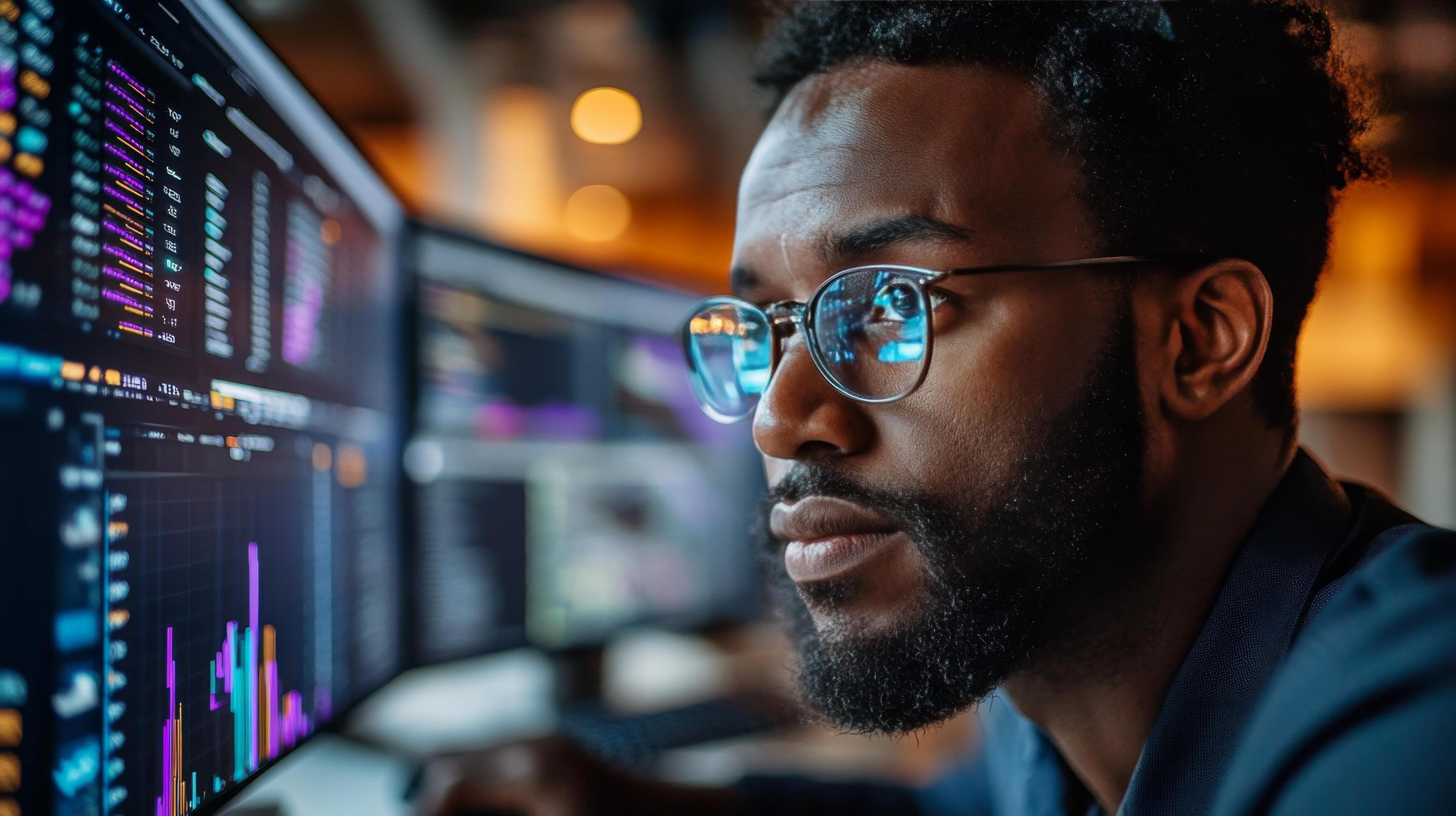 Young Professional Analyzing Data On Multiple Computer Screens In A Modern Office Setting