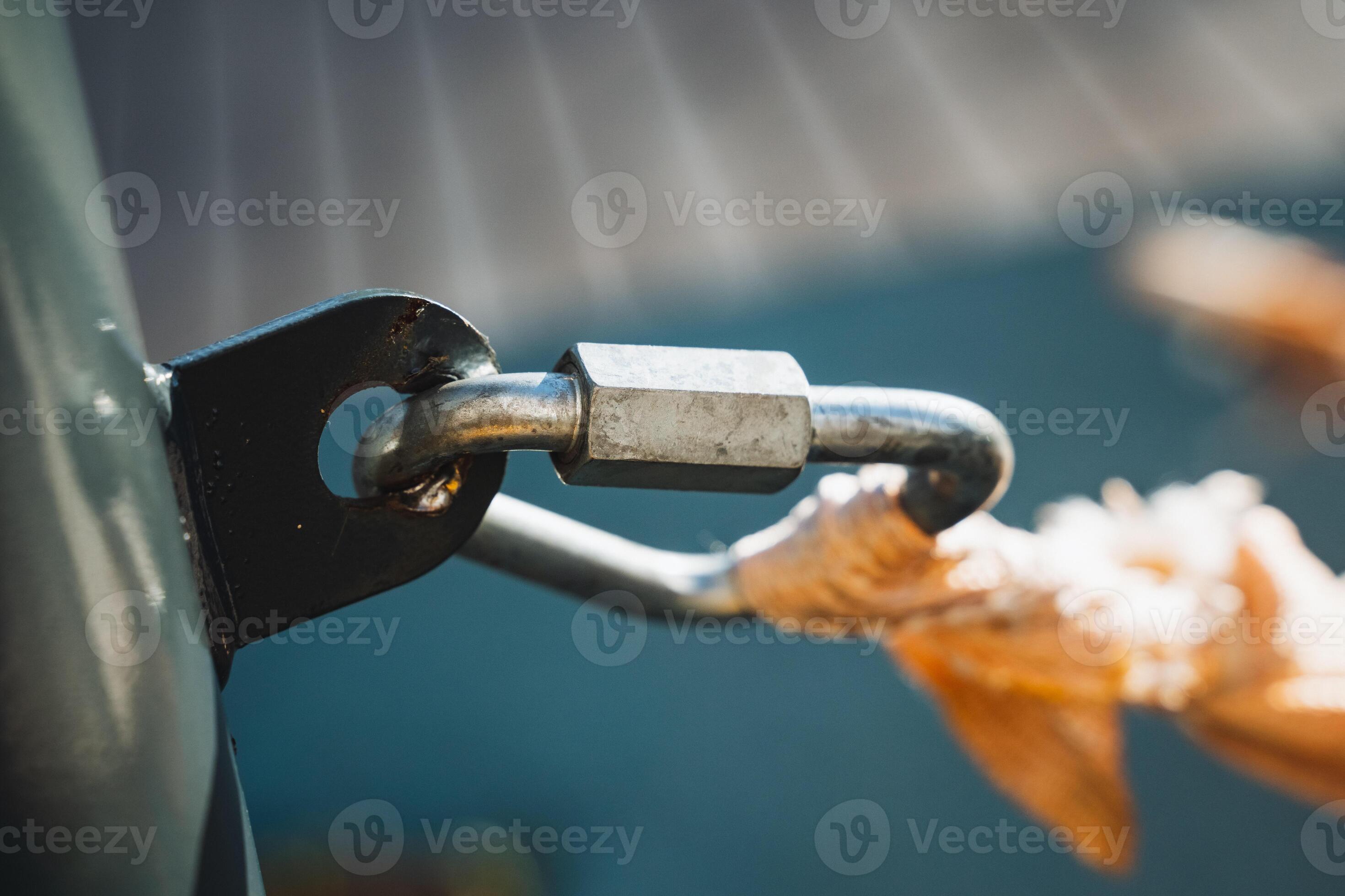 The image presents a detailed closeup of a sturdy metal hook, which has a flexible hose securely ...