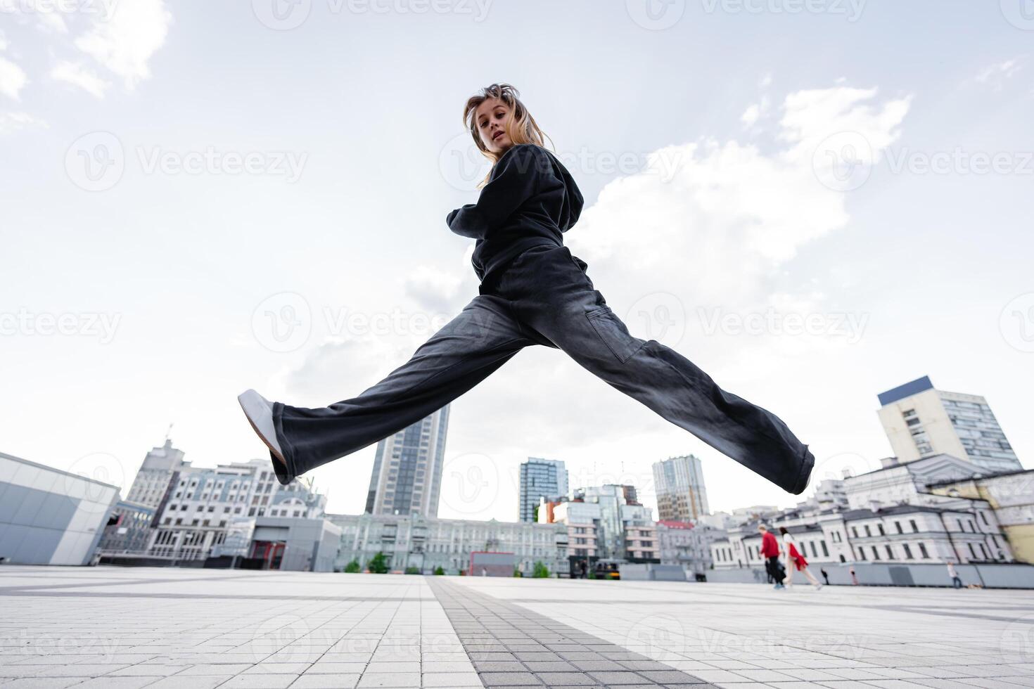 Young woman jumping across an urban square with buildings in the background 54868192 Stock Photo ...