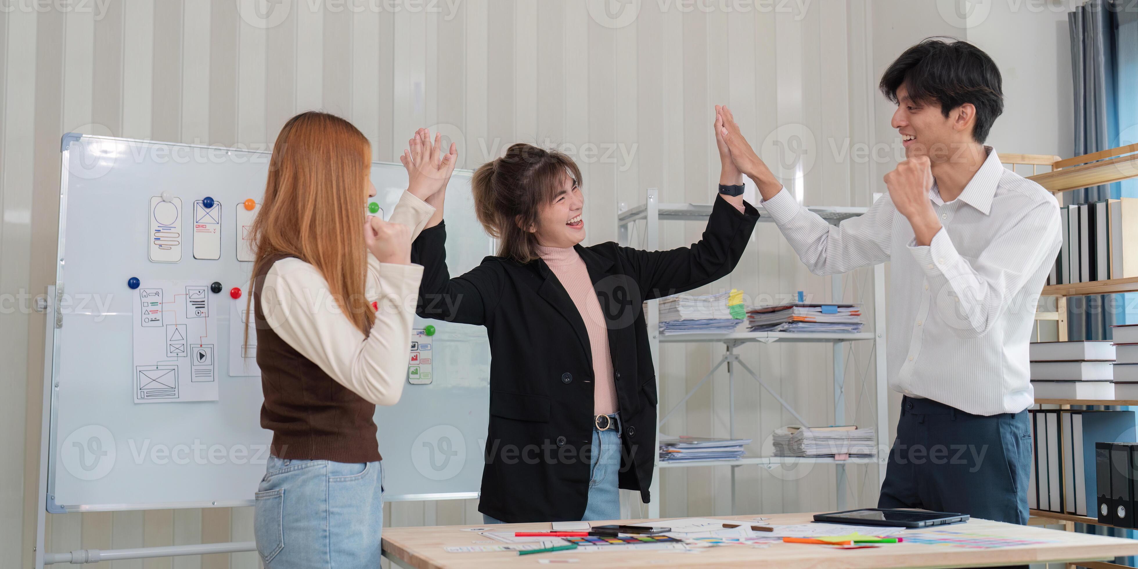 Excited UX UI team celebrating progress with high fives in a modern collaborative workspace ...