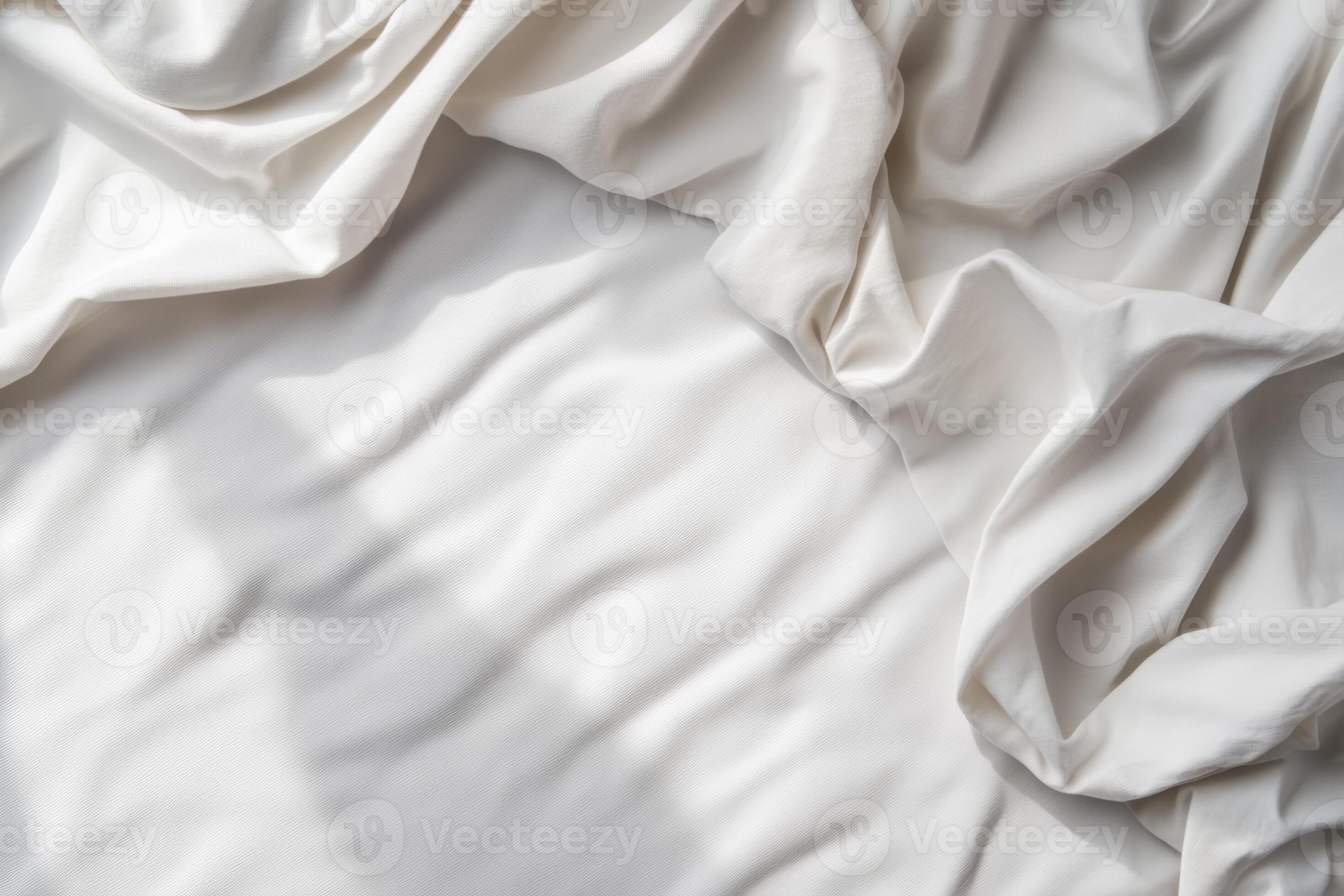Soft white fabric draped elegantly on a surface, creating gentle folds and shadows in natural ...