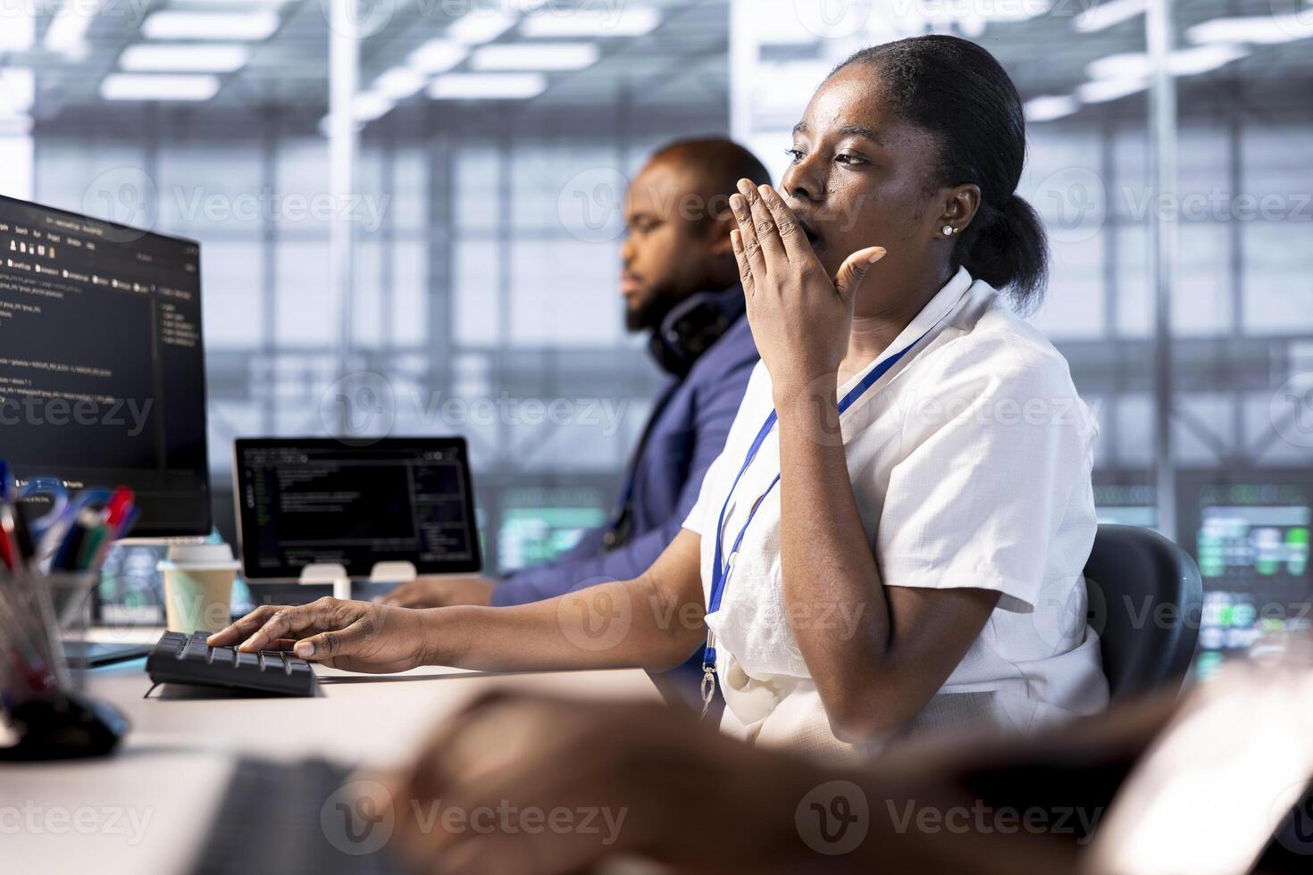 Bored data center technician yawning while creating technical documentation for software ...