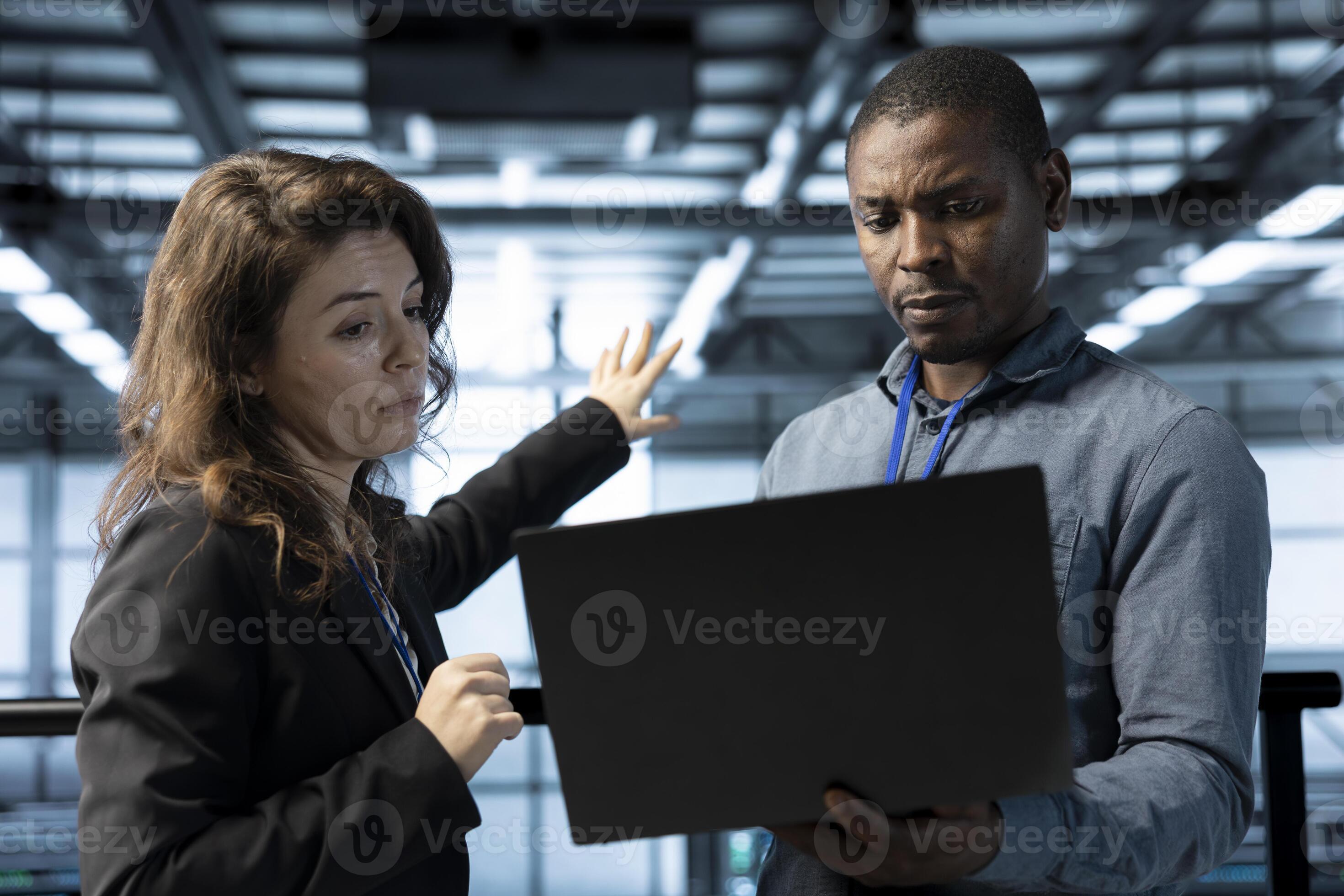 Computer scientists in data center automating routine maintenance tasks with laptop, executing ...