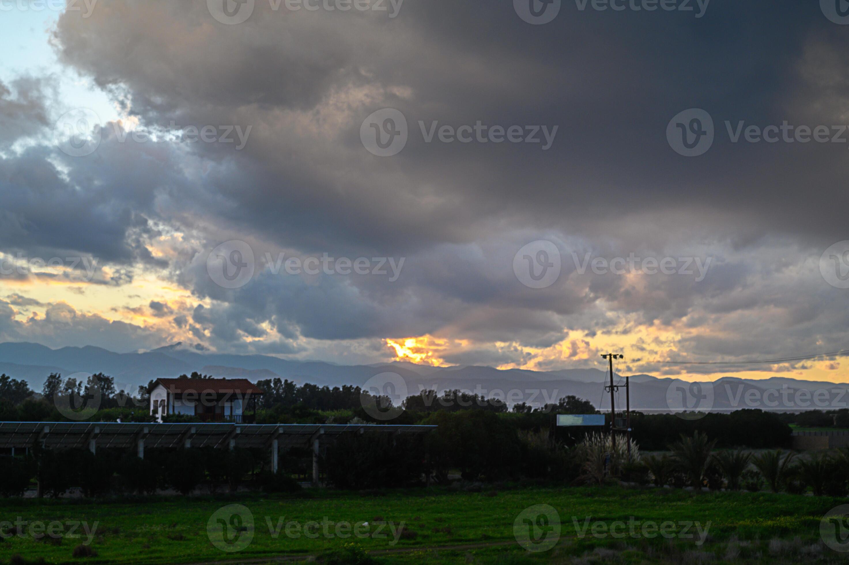 Majestic sunset clouds cast shadows over a serene countryside landscape near a charming ...