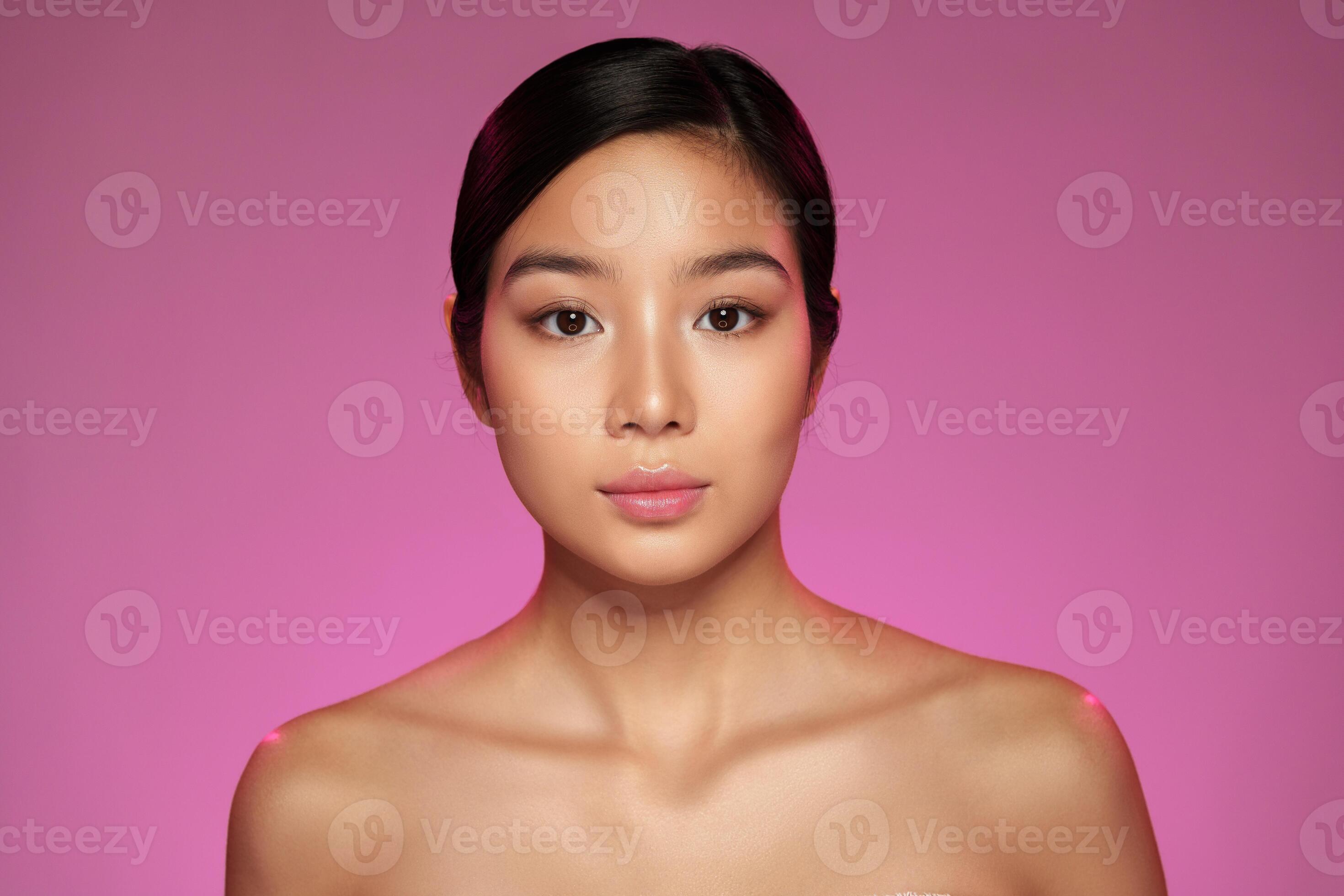 Portrait of a woman with a subtle expression against a vibrant pink ...