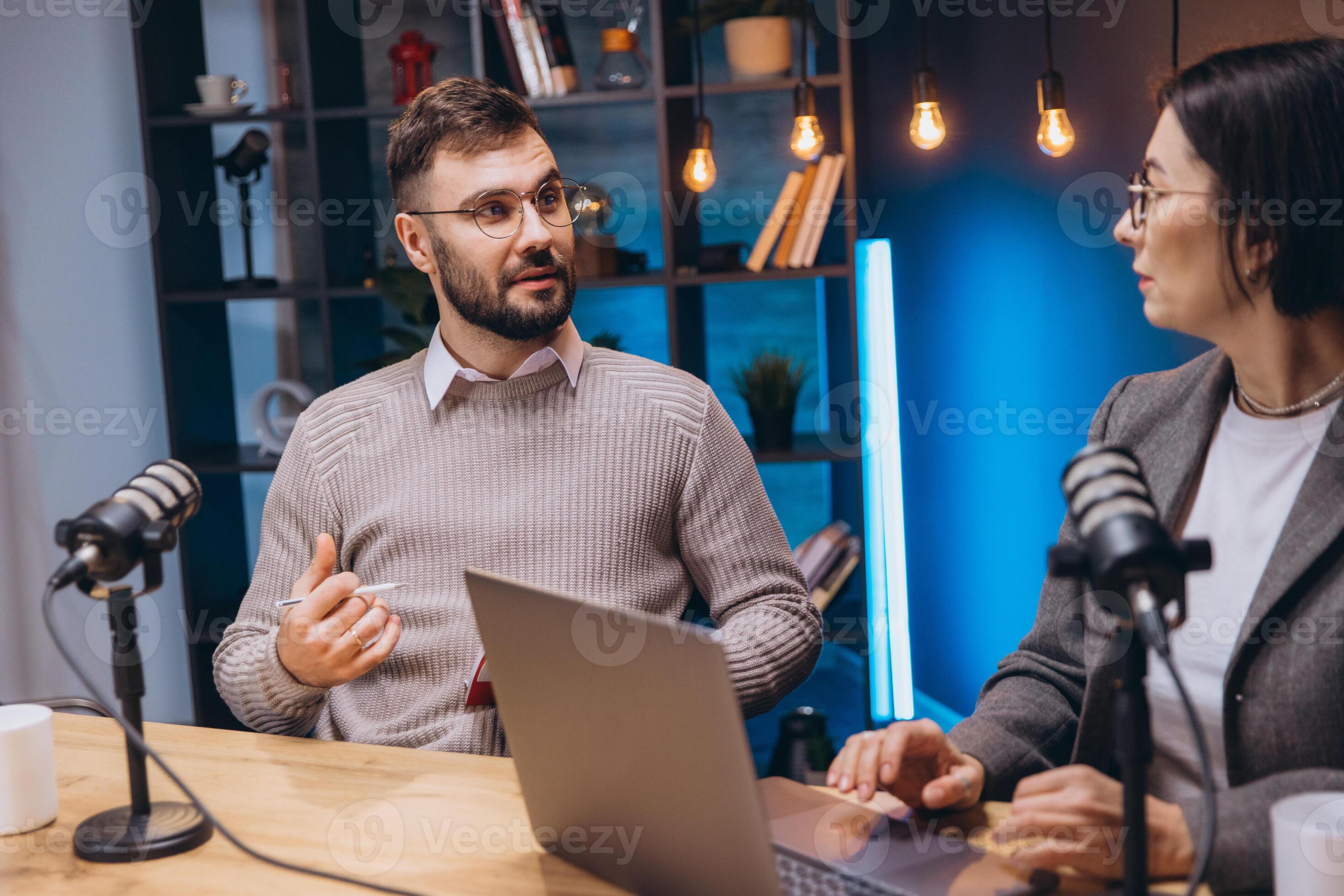 Two content creators recording their podcast in a studio, using professional equipment, laptop ...