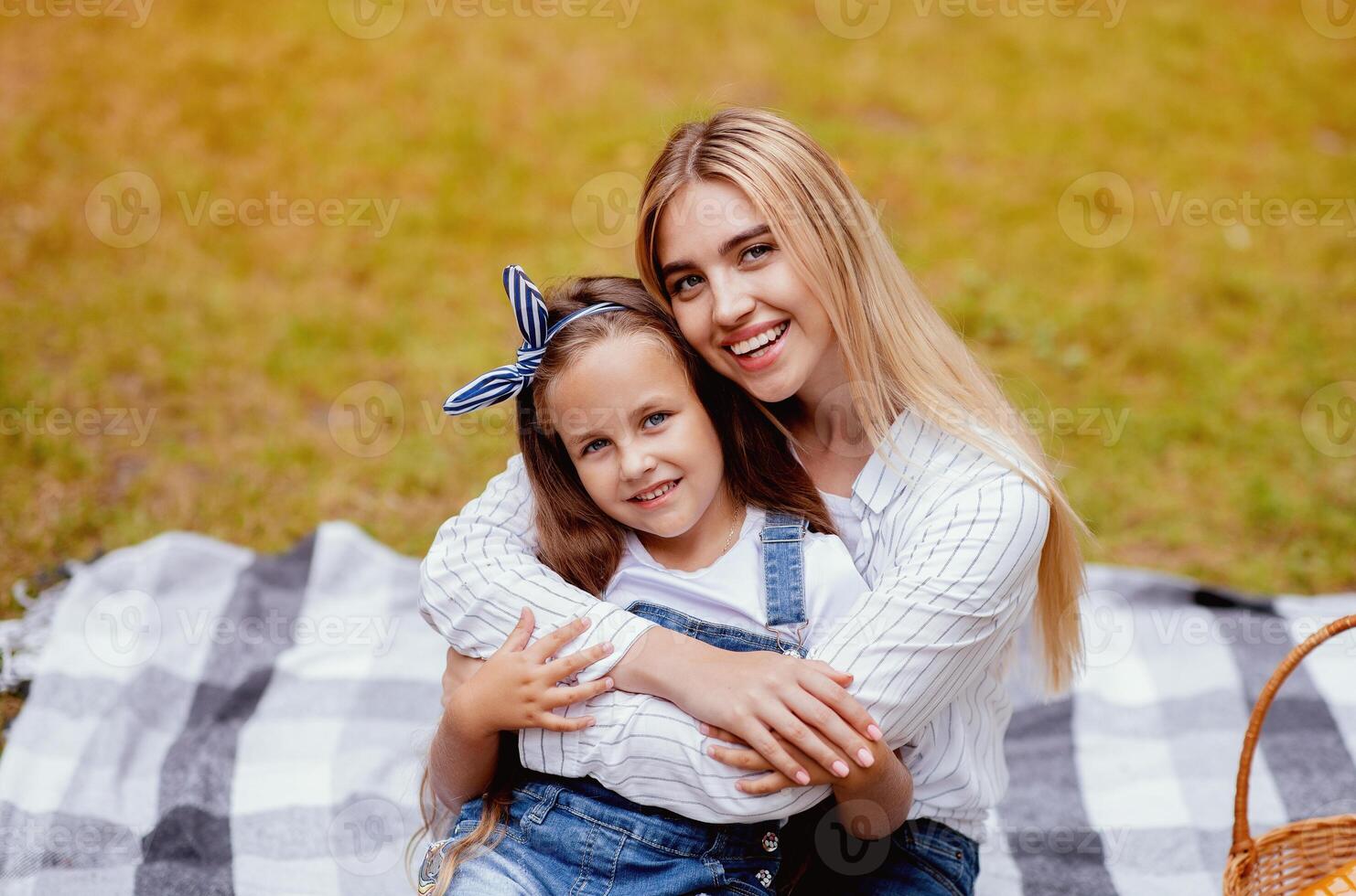 Happy Mother Hugging Her Little Daughter Sitting On Blanket During Picnic In Countryside. Mom's ...