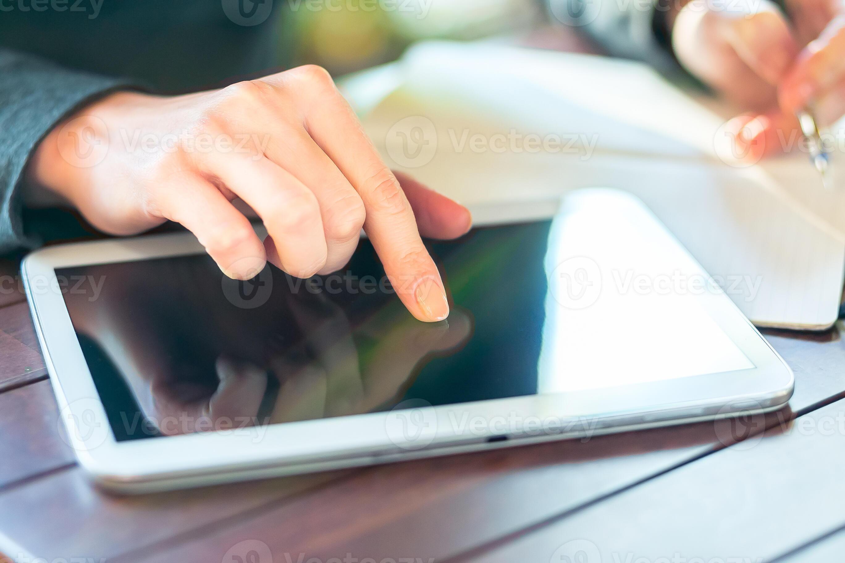 Engaged user interacting with tablet device while taking notes on a ...