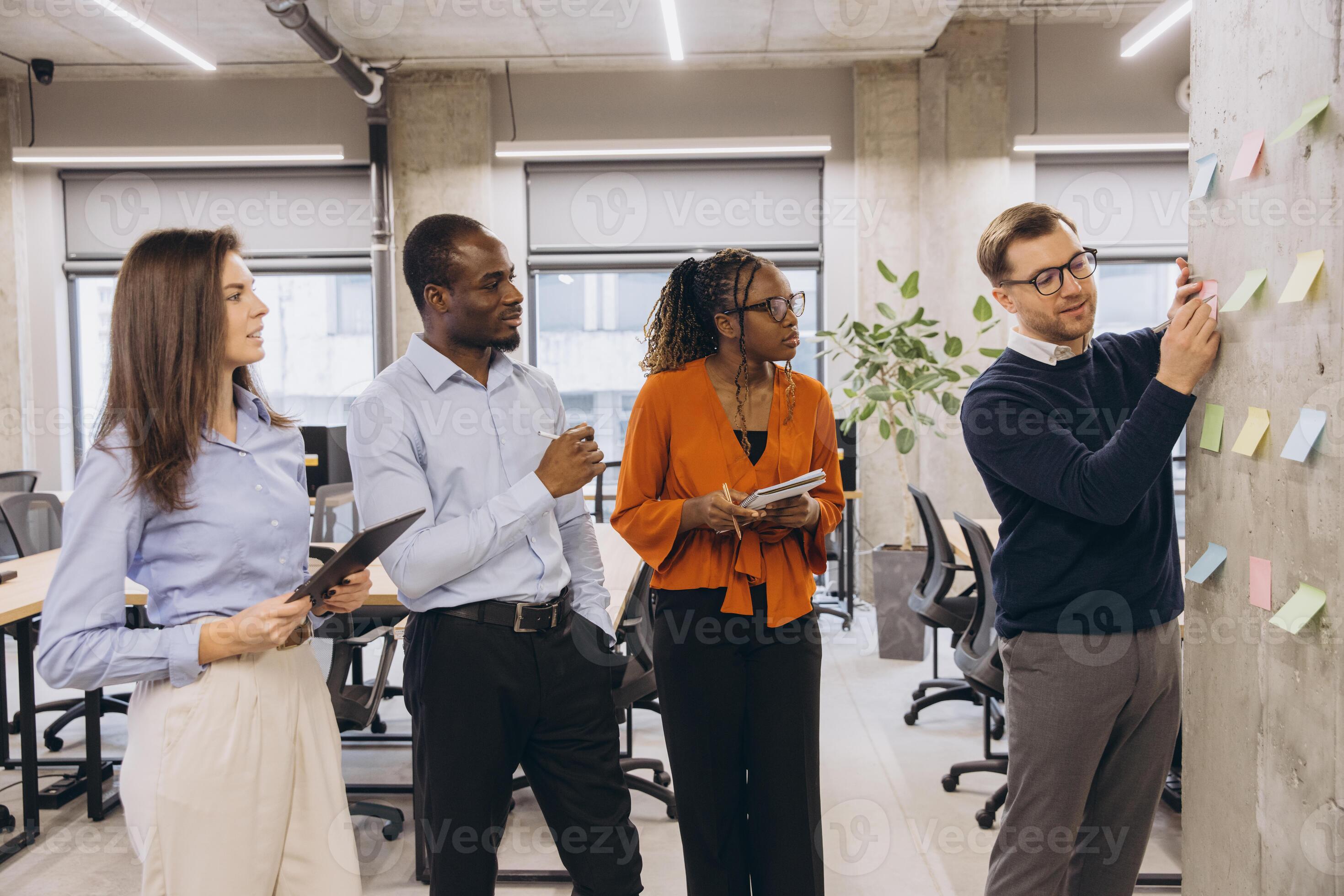 Business Team Collaborating On A Project Using Sticky Notes On A Wall