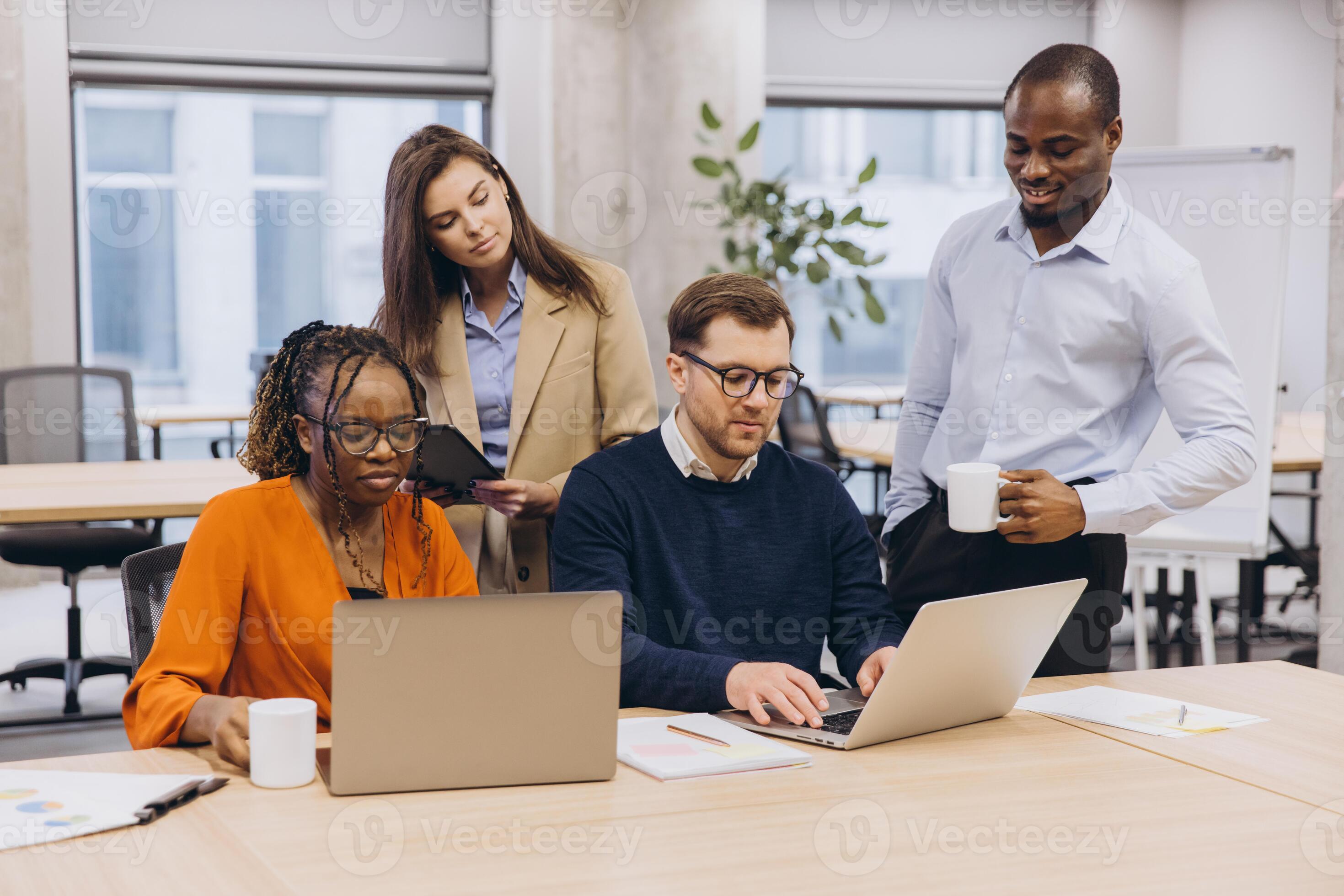 Diverse professionals collaborating, working together on project using laptops, sharing insights ...