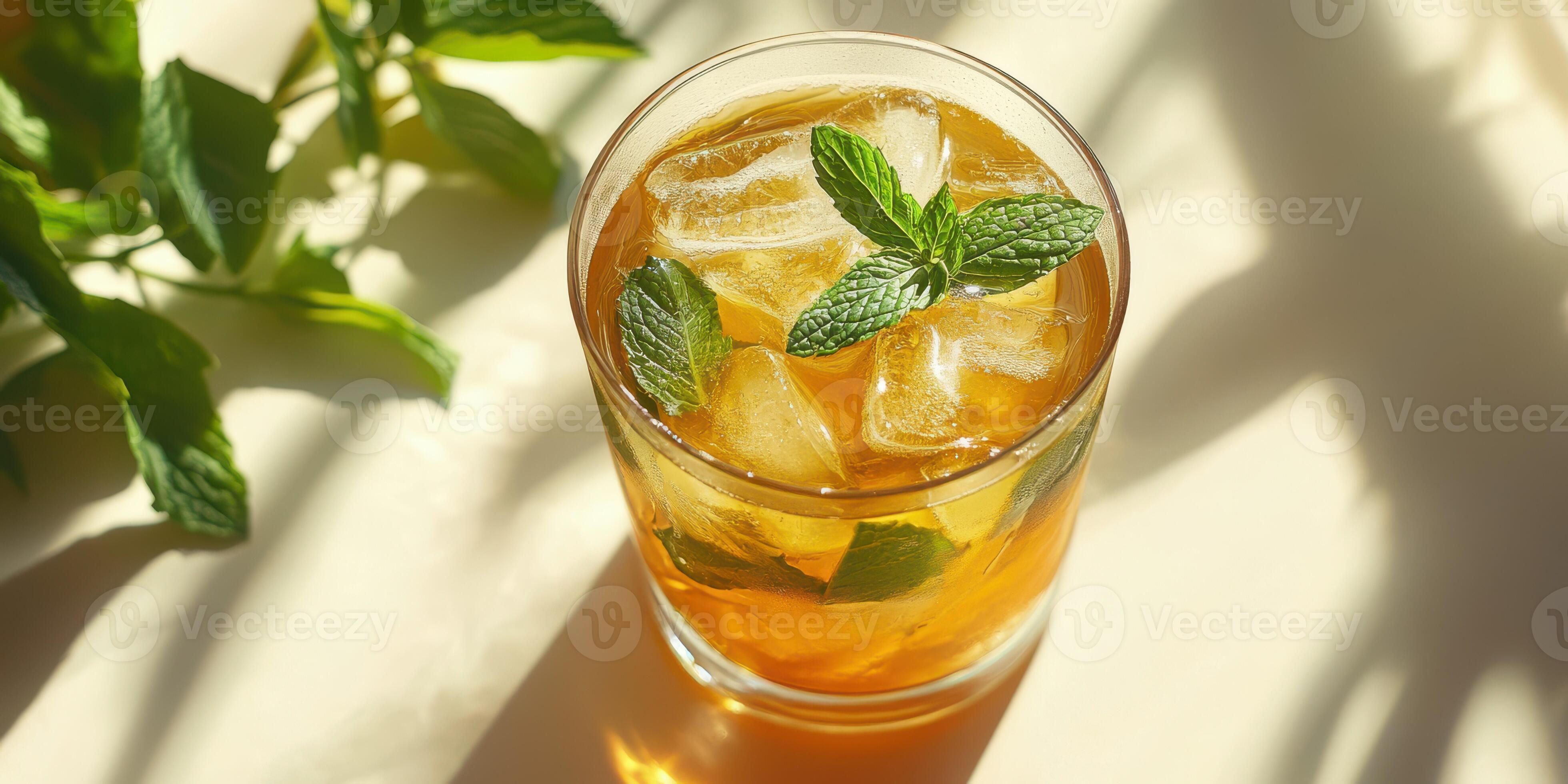 Refreshing mint iced tea served in a clear glass with ice cubes and fresh mint leaves on a ...