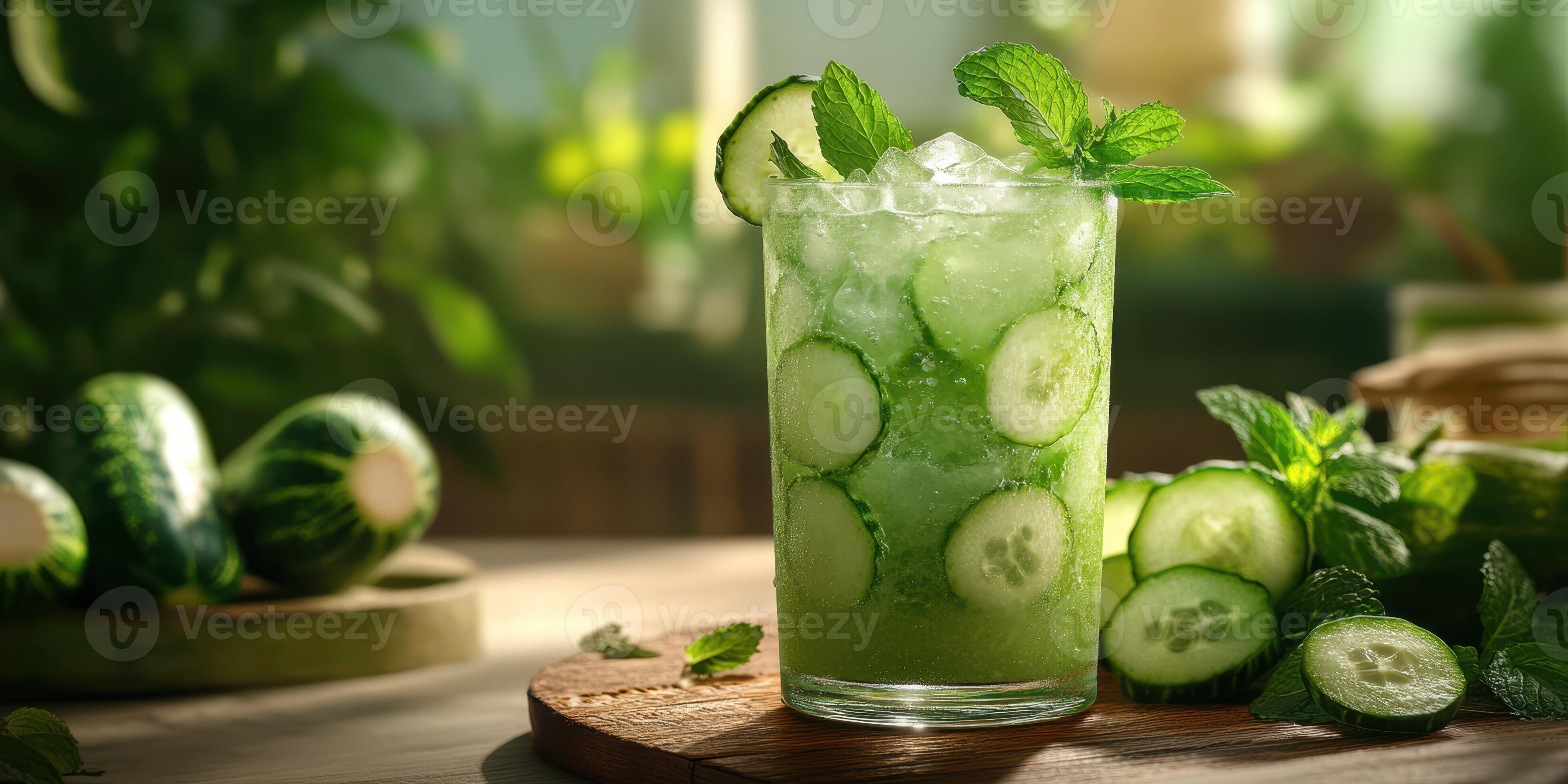 Refreshing cucumber mint cooler with ice served in a tall glass on a wooden countertop ...