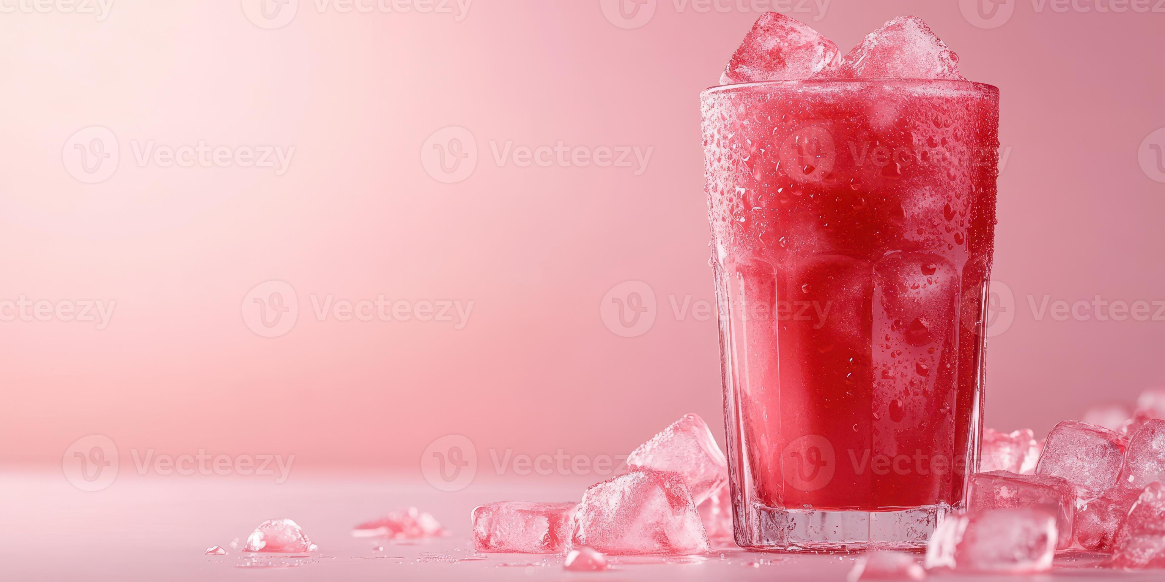 Refreshing pink drink filled with ice served in a clear glass against a soft pink background ...