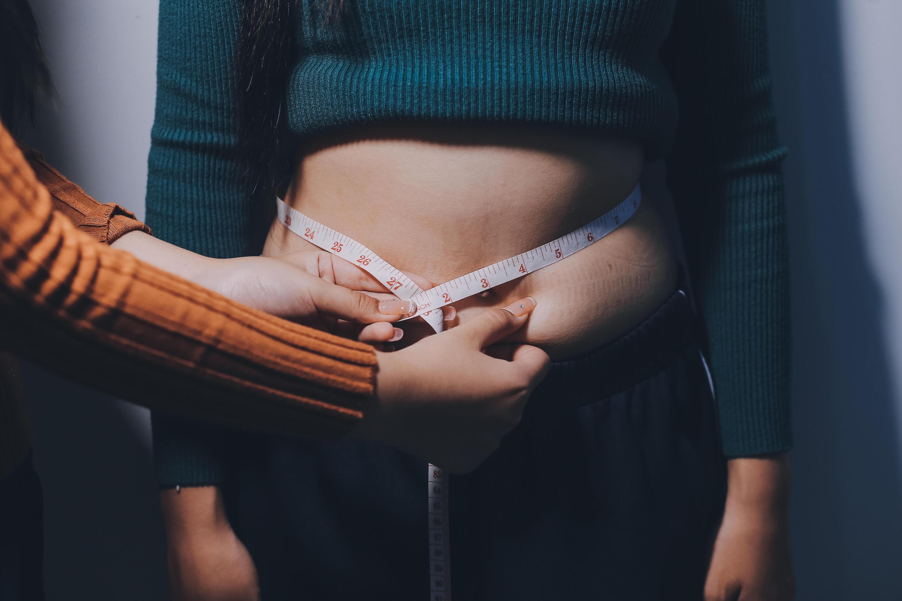 A woman measuring her waist with a tape measure 56496818 Stock Photo at Vecteezy