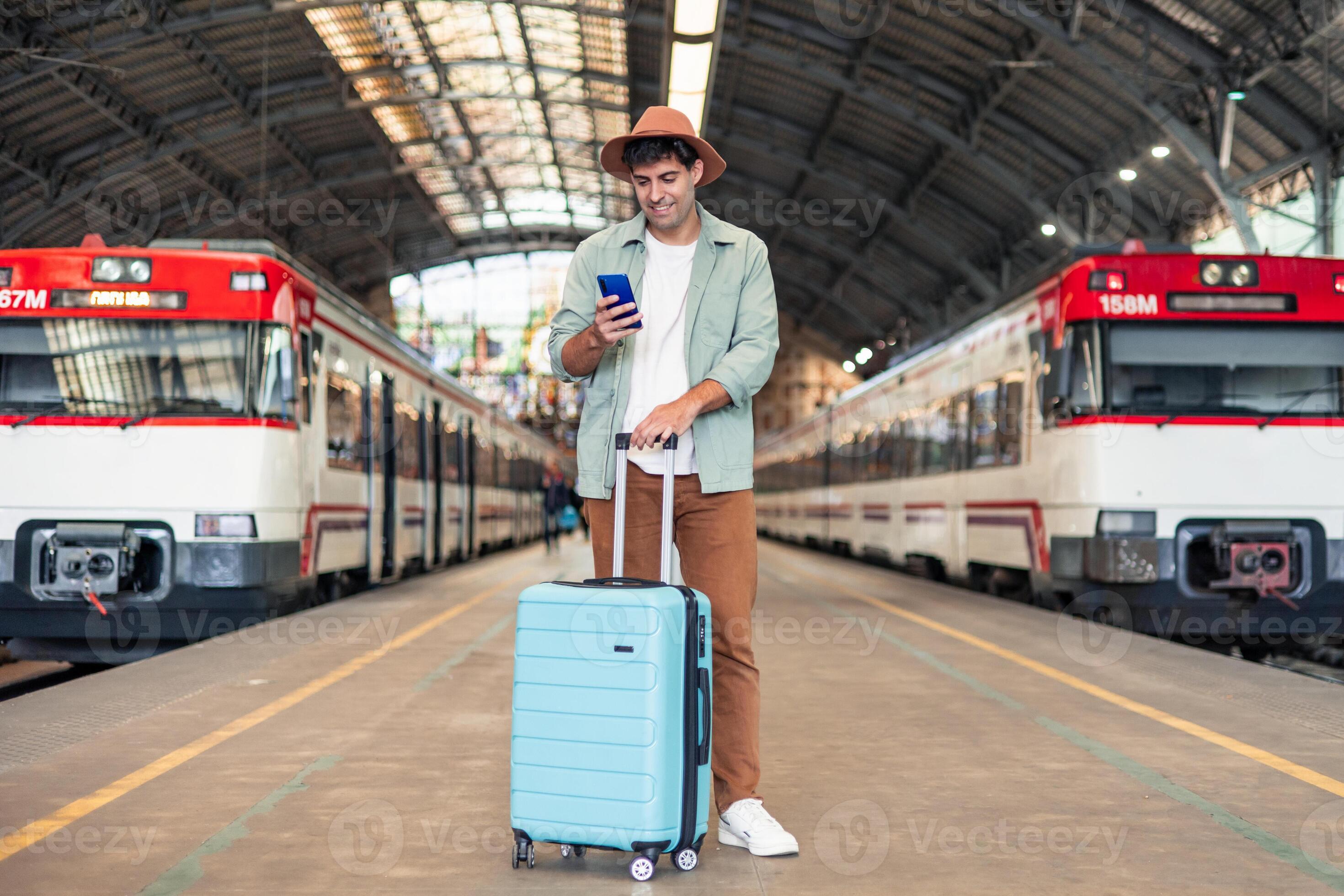 latin Tourist texting smartphone while waiting for train at station ...