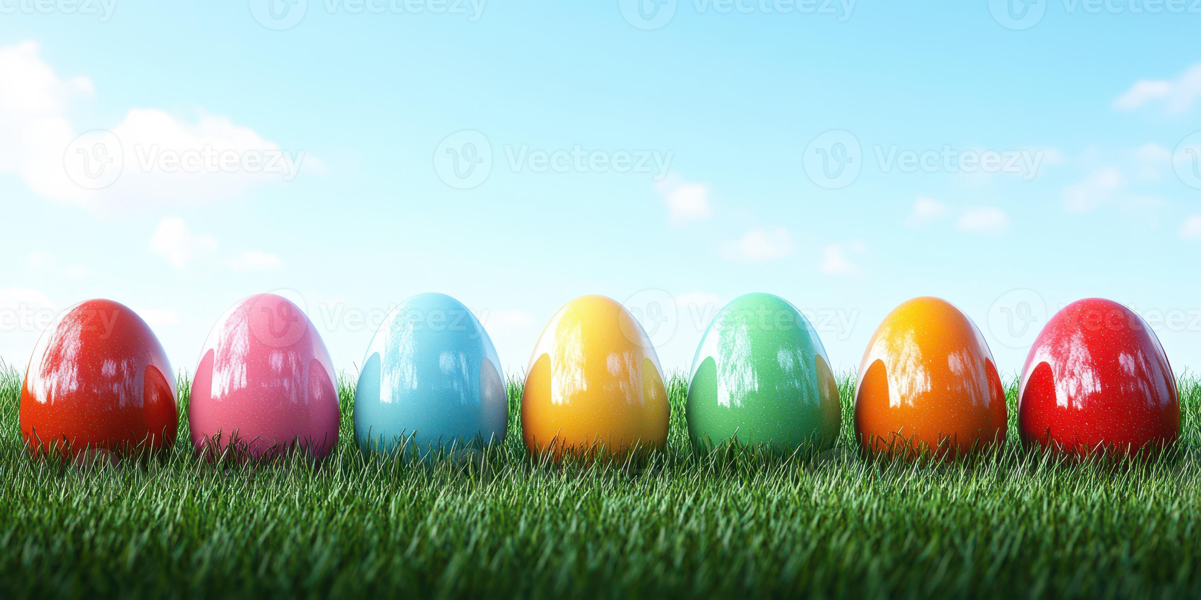 Colorful Easter eggs lined up on green grass under a clear blue sky ...