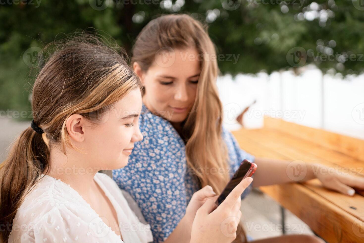 Smartphone, Mother, Daughter. Outdoors, park bench, sharing, summertime, family bonding ...