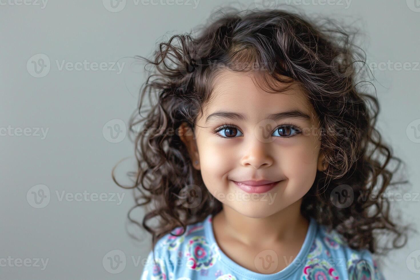 A cheerful young girl with curly hair smiles brightly, showcasing her ...