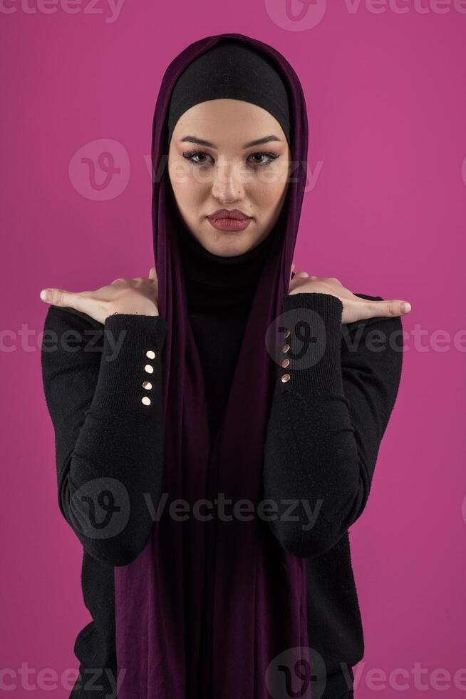 Beautiful Muslim woman in a hijab posing elegantly in a studio with a pink background. 57470813 ...