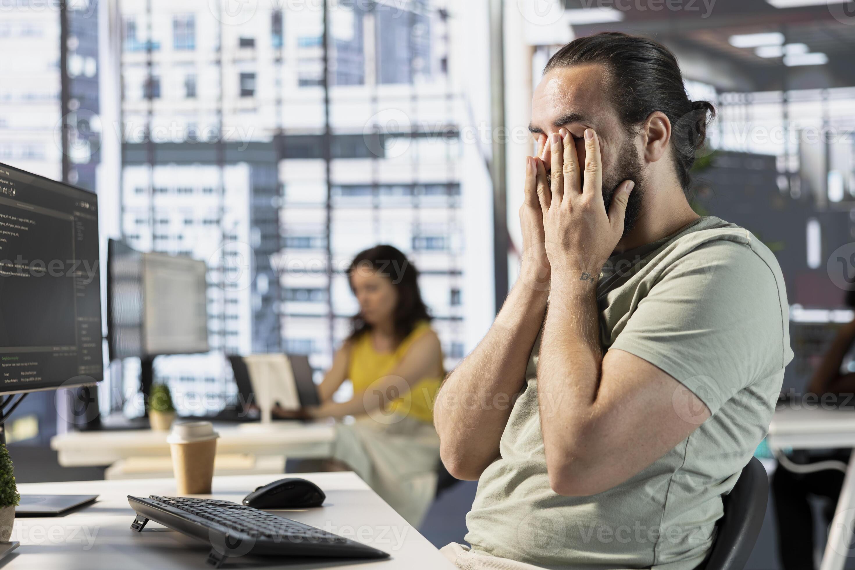 Exhausted man at work rubbing eyes, creating machine learning models that can process and ...