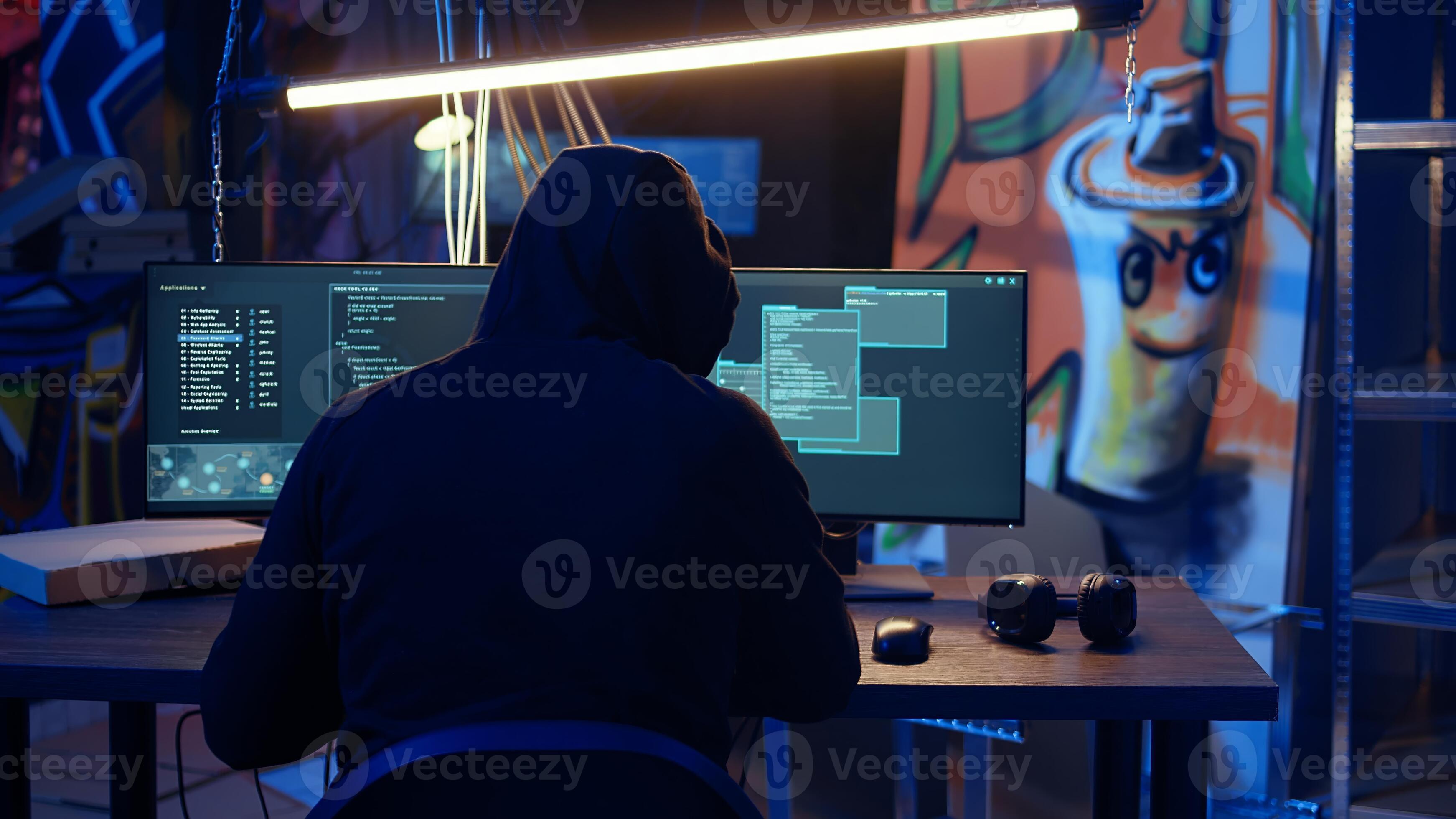 Hooded man in underground hideaway utilizing technical knowhow of bugs and exploits to break ...