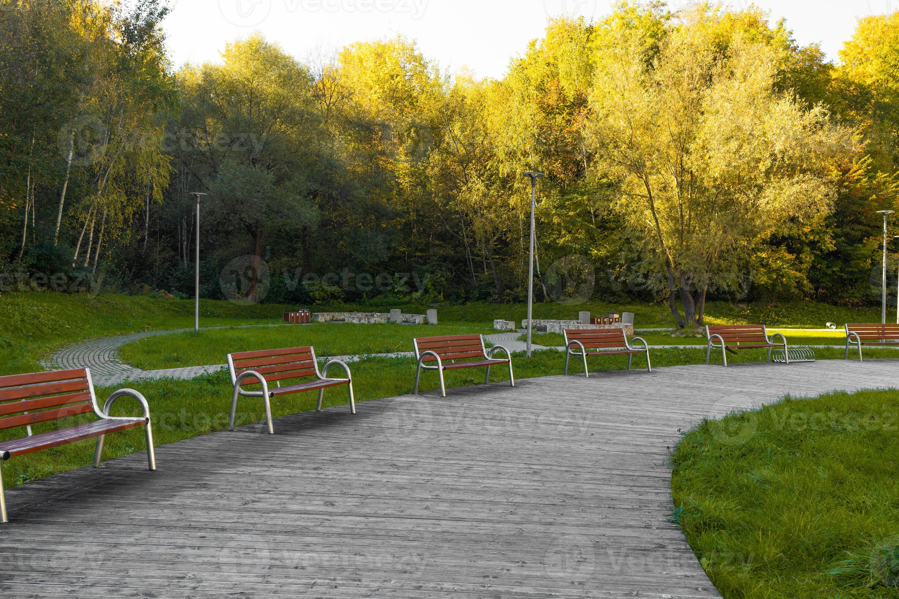 A modern wooden benches with trash bin standing in the park. Comfortable bench in recreation ...