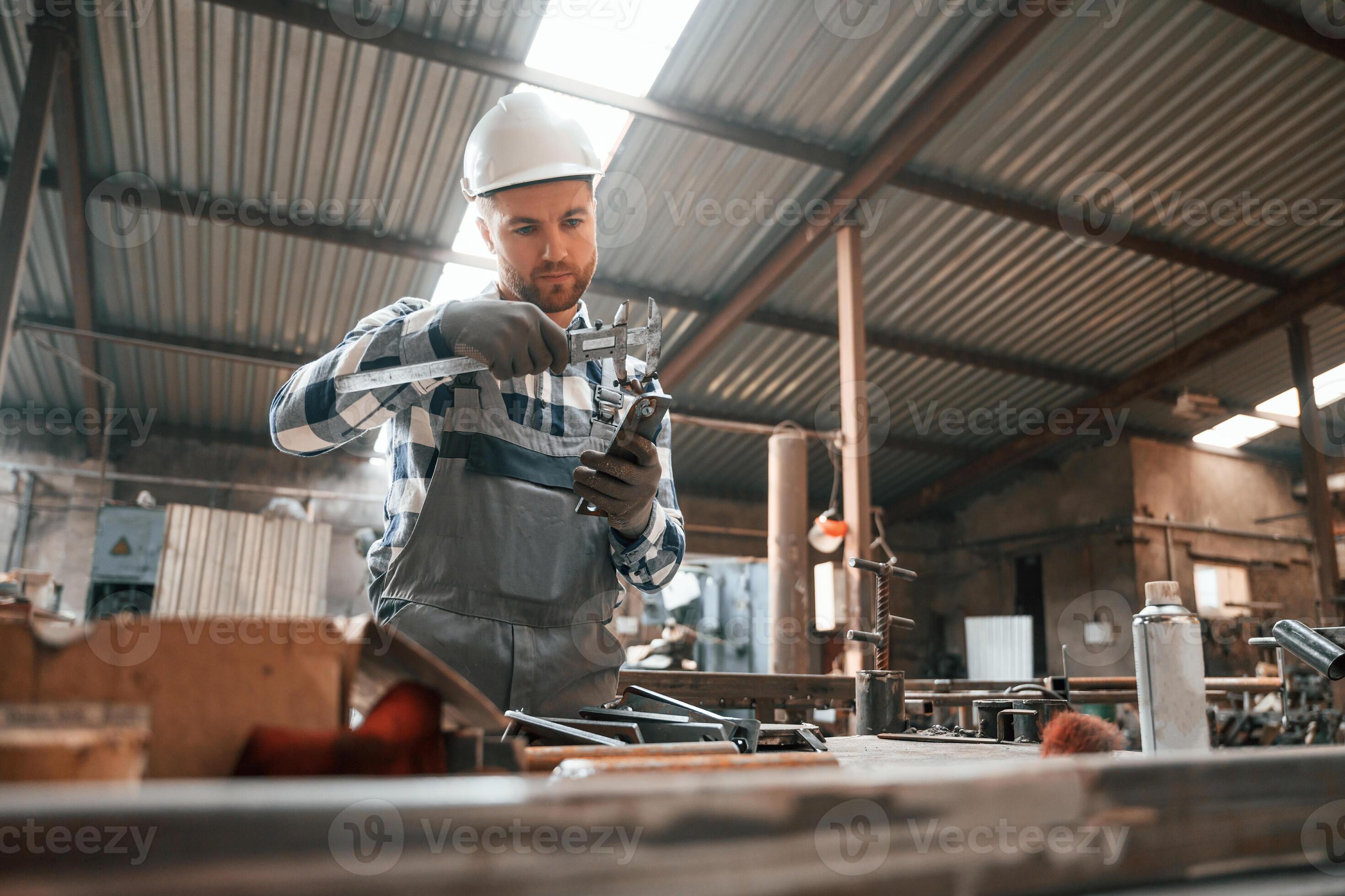Measuring the object. Factory male worker in uniform is indoors 59175293 Stock Photo at Vecteezy