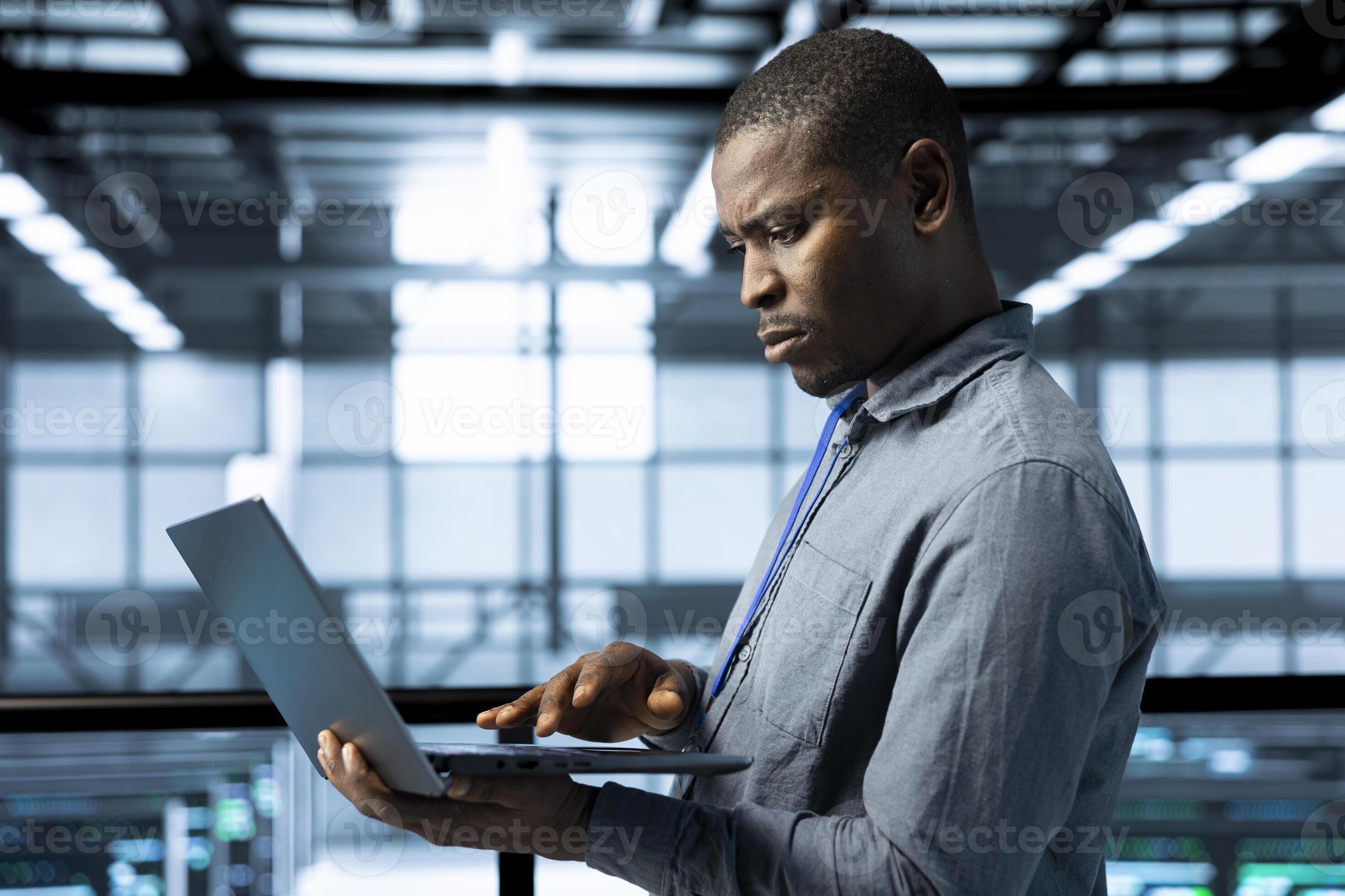 African American Engineer In Data Center With Laptop Automating Routine