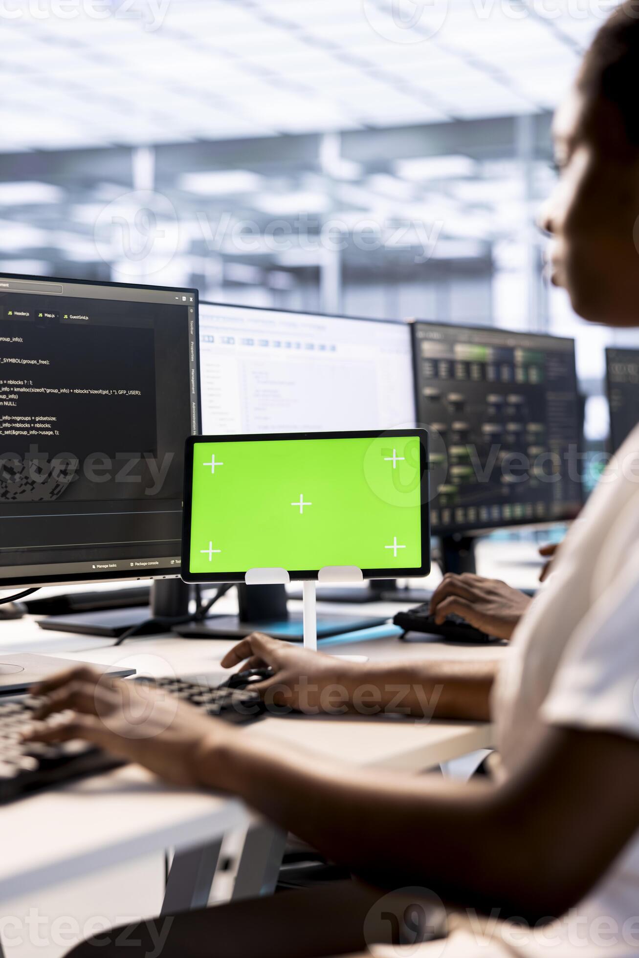 Computer scientist using green screen tablet to check for signs of failure in data center ...