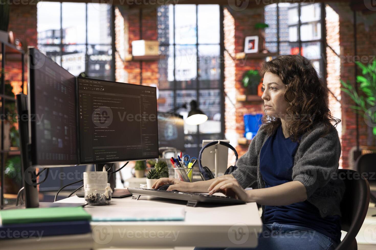 IT specialist at workstation programming on monitor and writing lines of code, using development ...