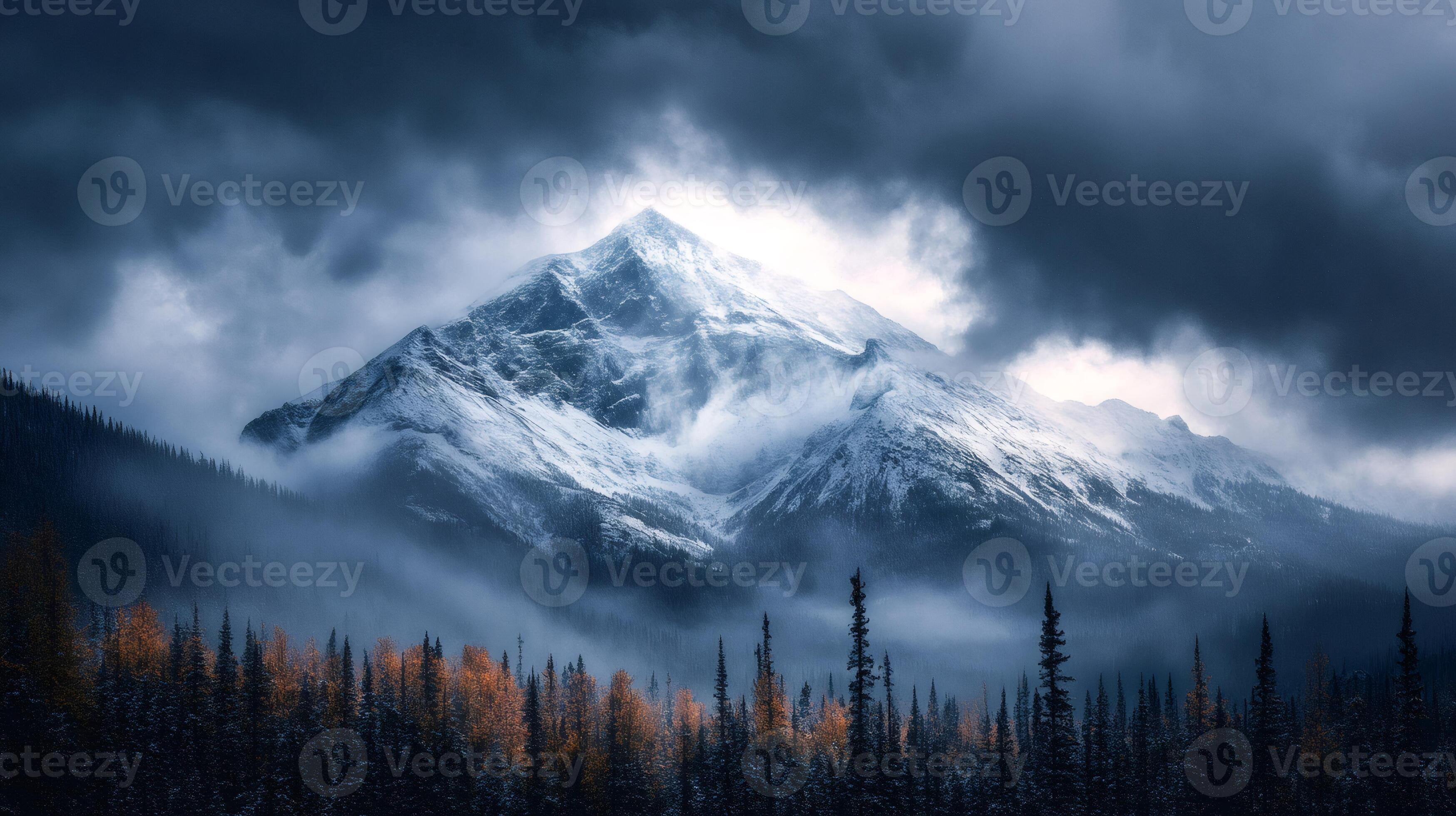 Snowy mountain peak emerging from misty forest under dramatic sky ...