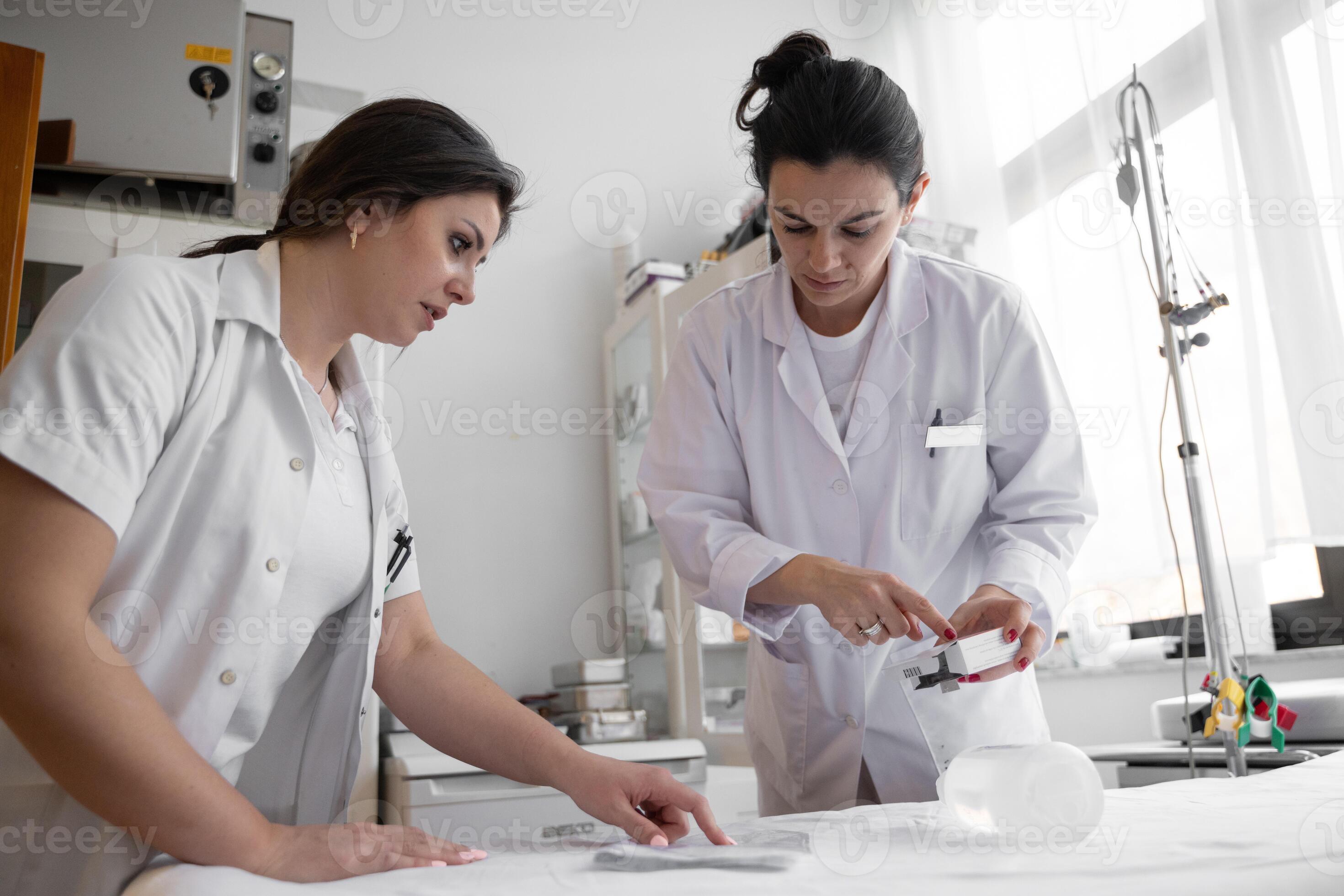 Two nurses in a hospital laboratory are carefully inspecting and preparing medications for ...