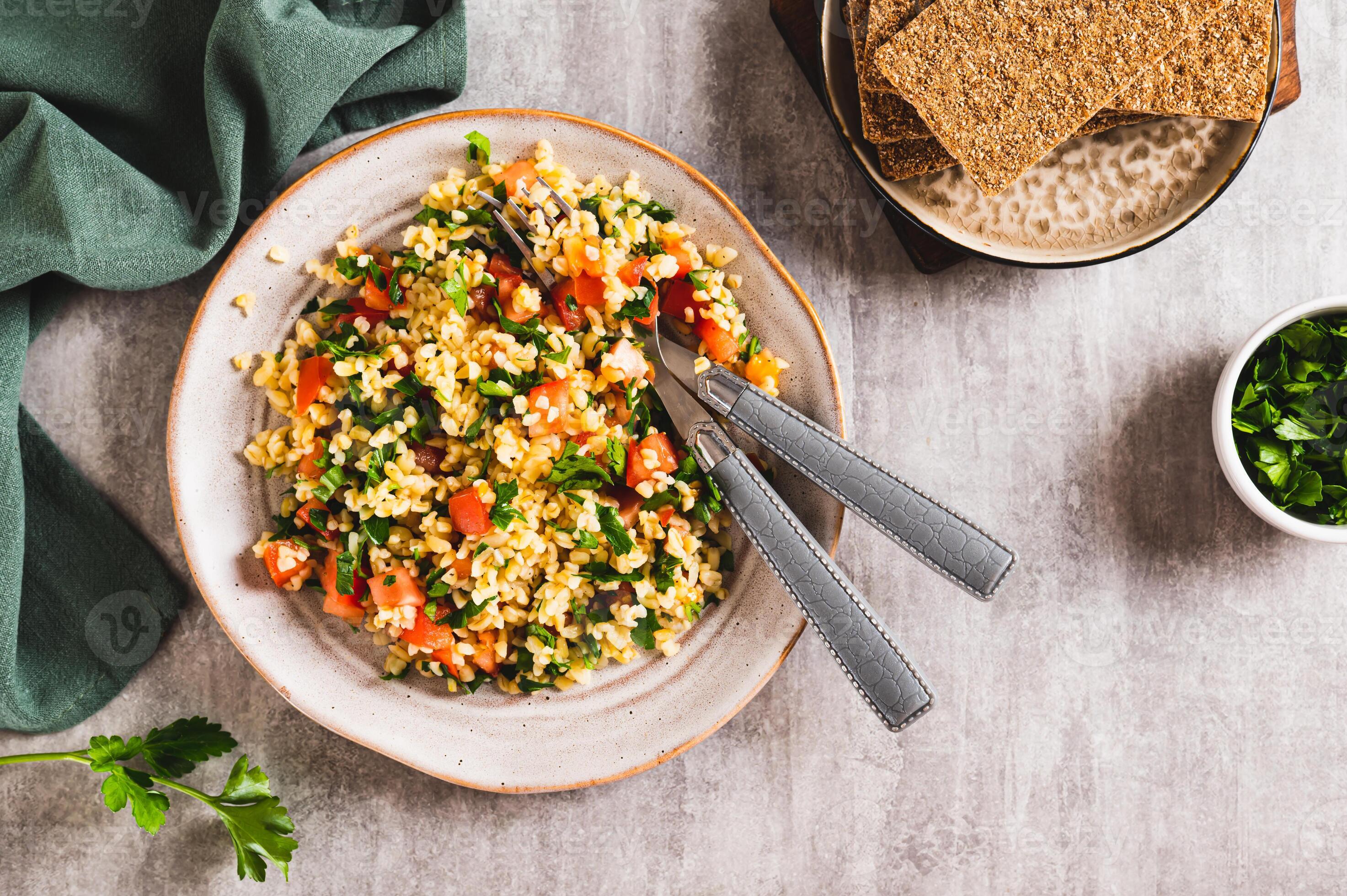 Tabbouleh salad with bulgur, tomato and parsley on a plate on the table ...