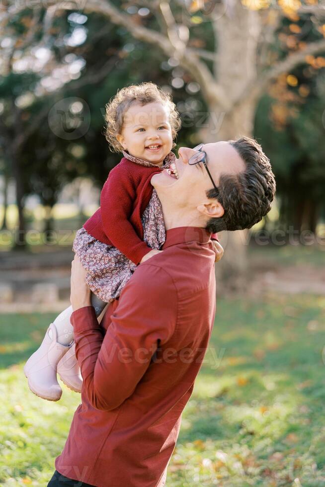 Laughing dad lifts high little girl hugging his neck 59885762 Stock Photo at Vecteezy