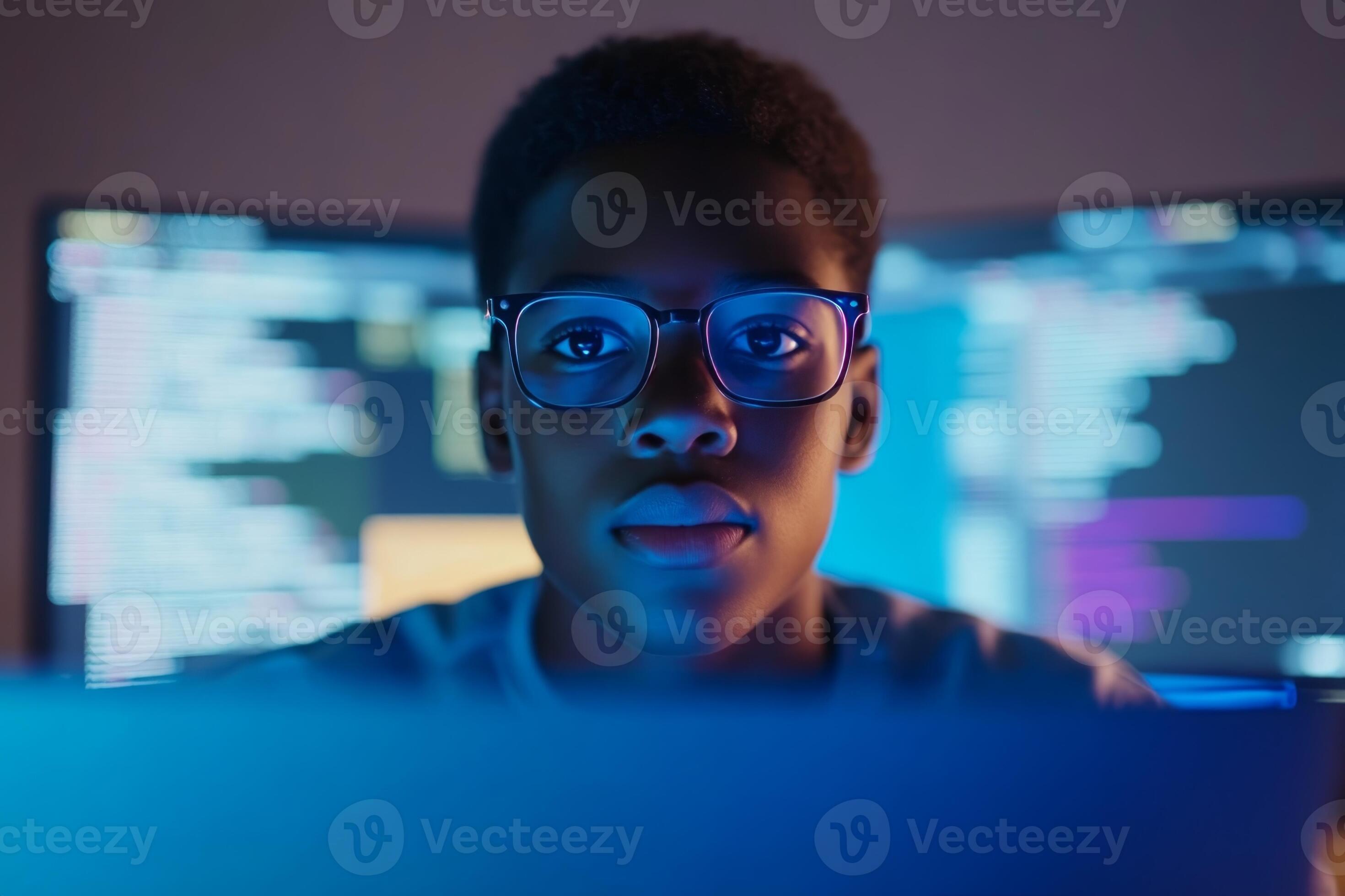 Focused young programmer coding in a dimly lit room with multiple screens displaying code and ...