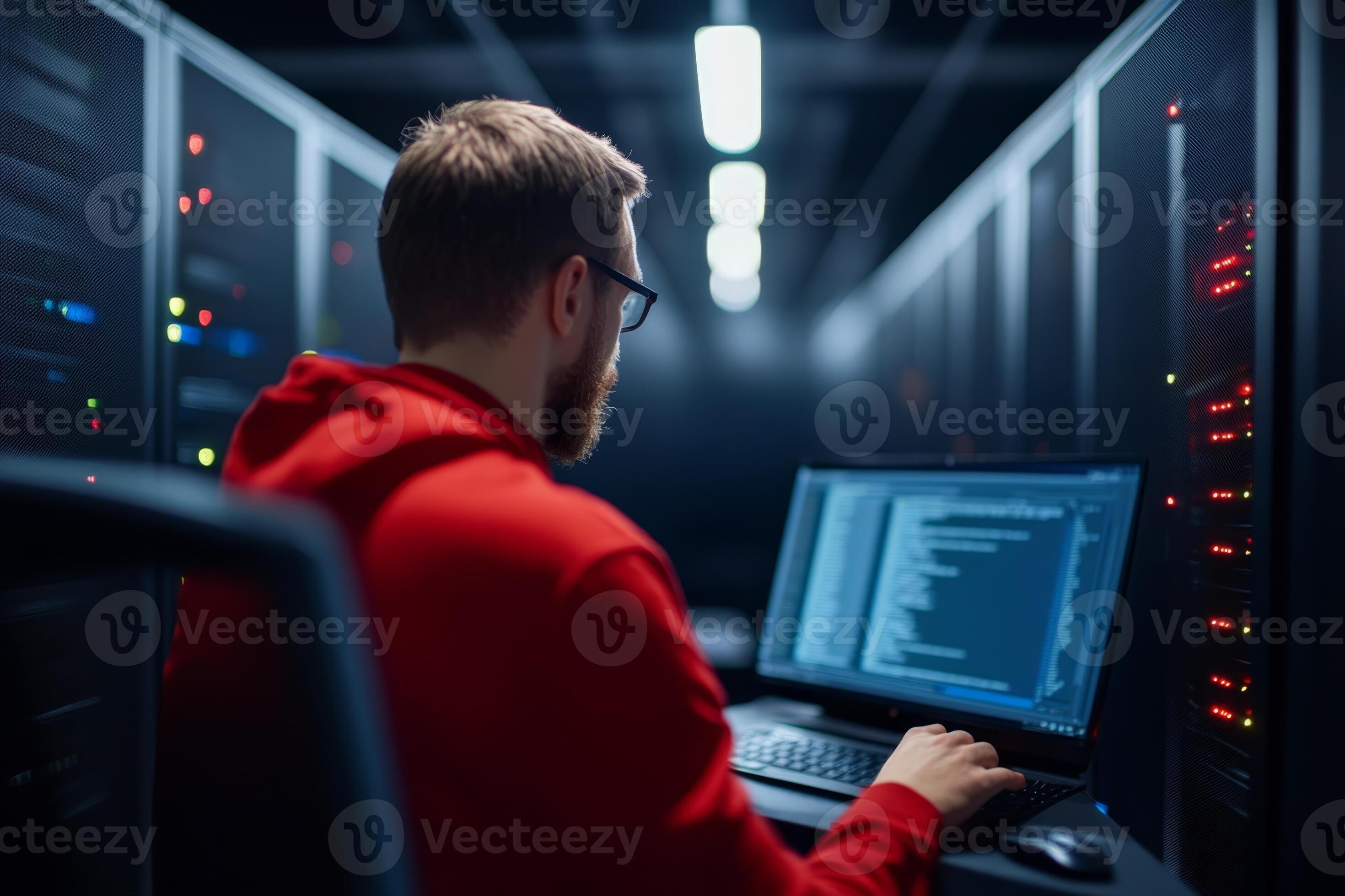 Backend developer coding in a server room at night with multiple screens and data servers ...