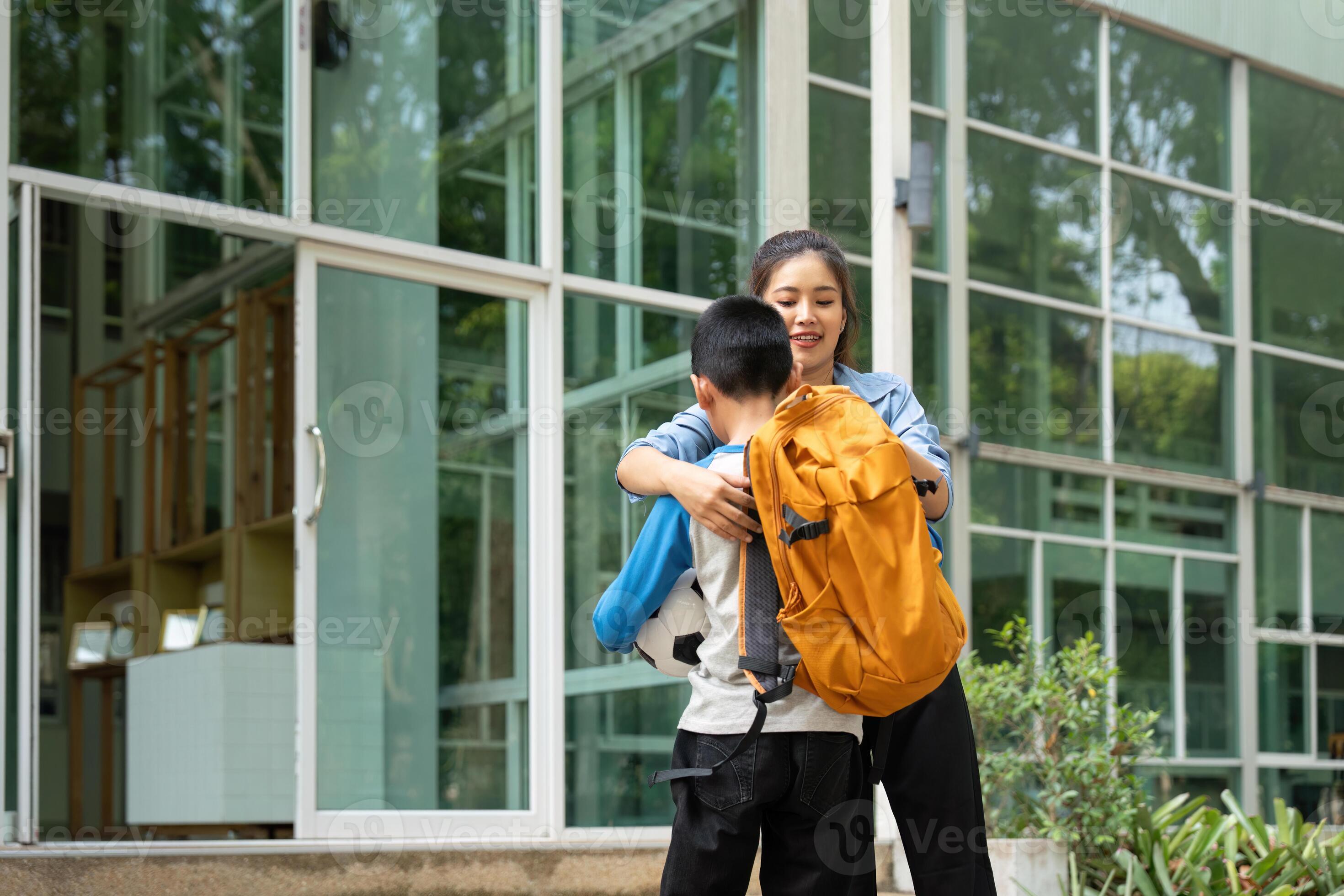 Family Support and School Arrival. A mother helps her son get ready for school while holding his ...