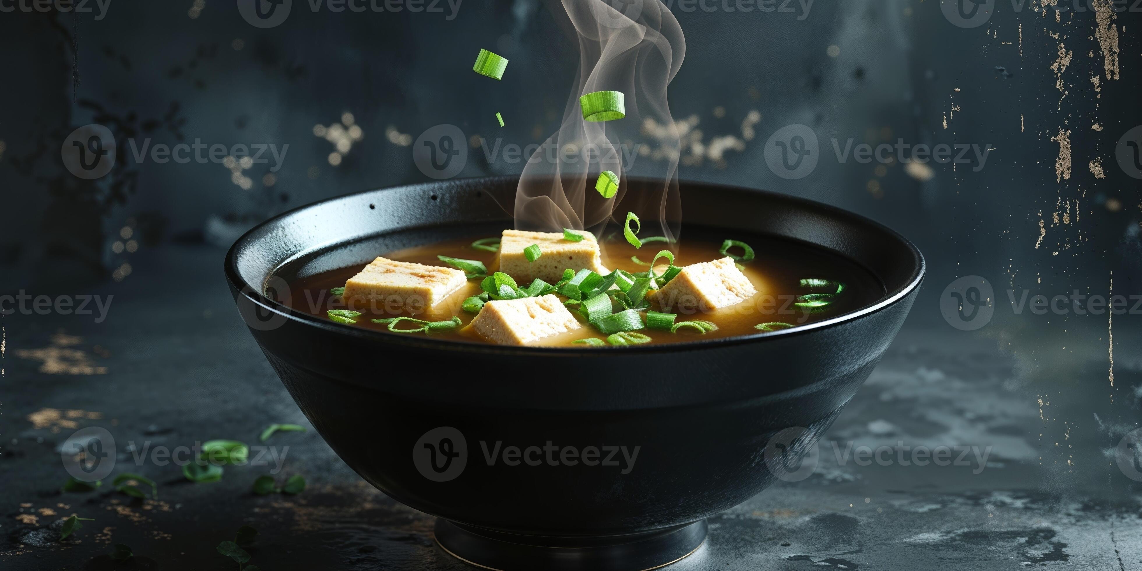 Classic Miso Soup in Black Bowl Featuring Tofu Cubes Garnished with Chopped Scallions on a Dark ...