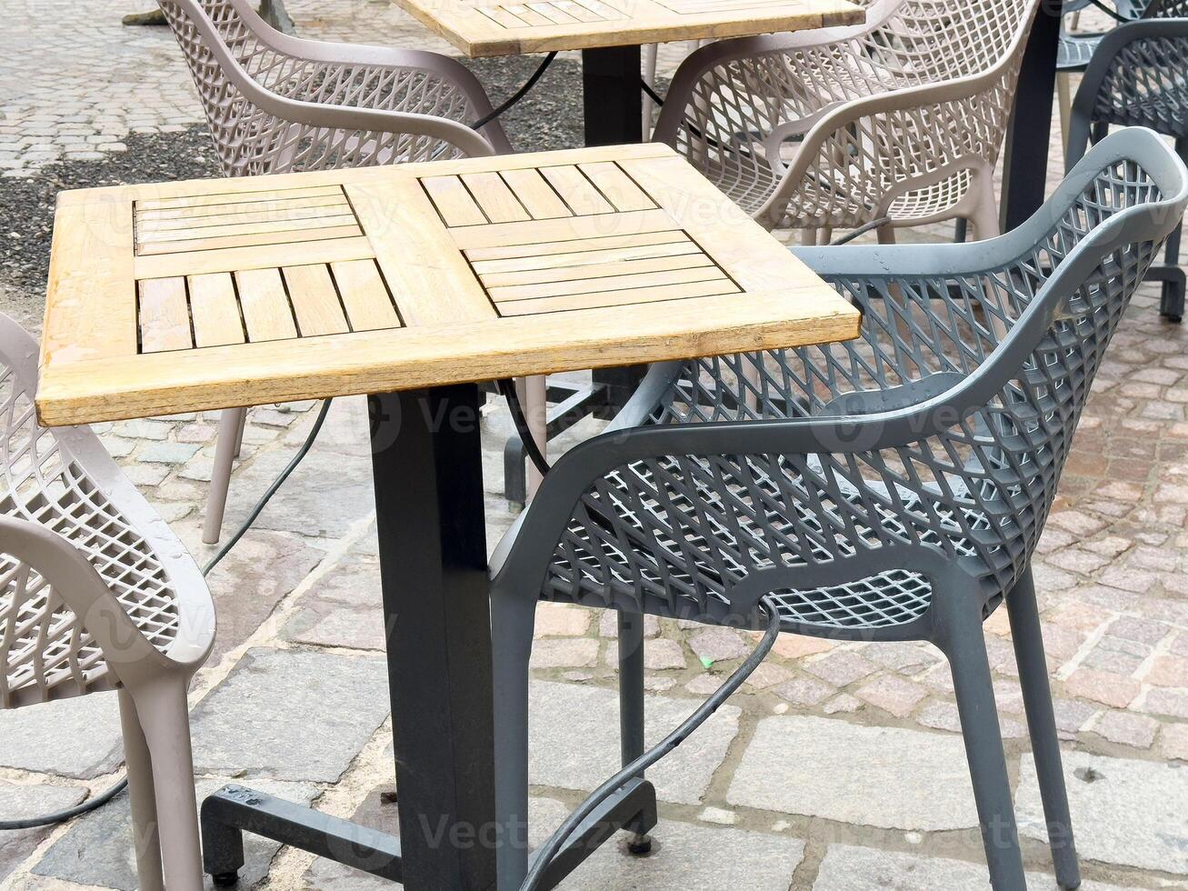Outdoor cafe seating with wooden tables and metal chairs on cobblestone patio 63465685 Stock ...