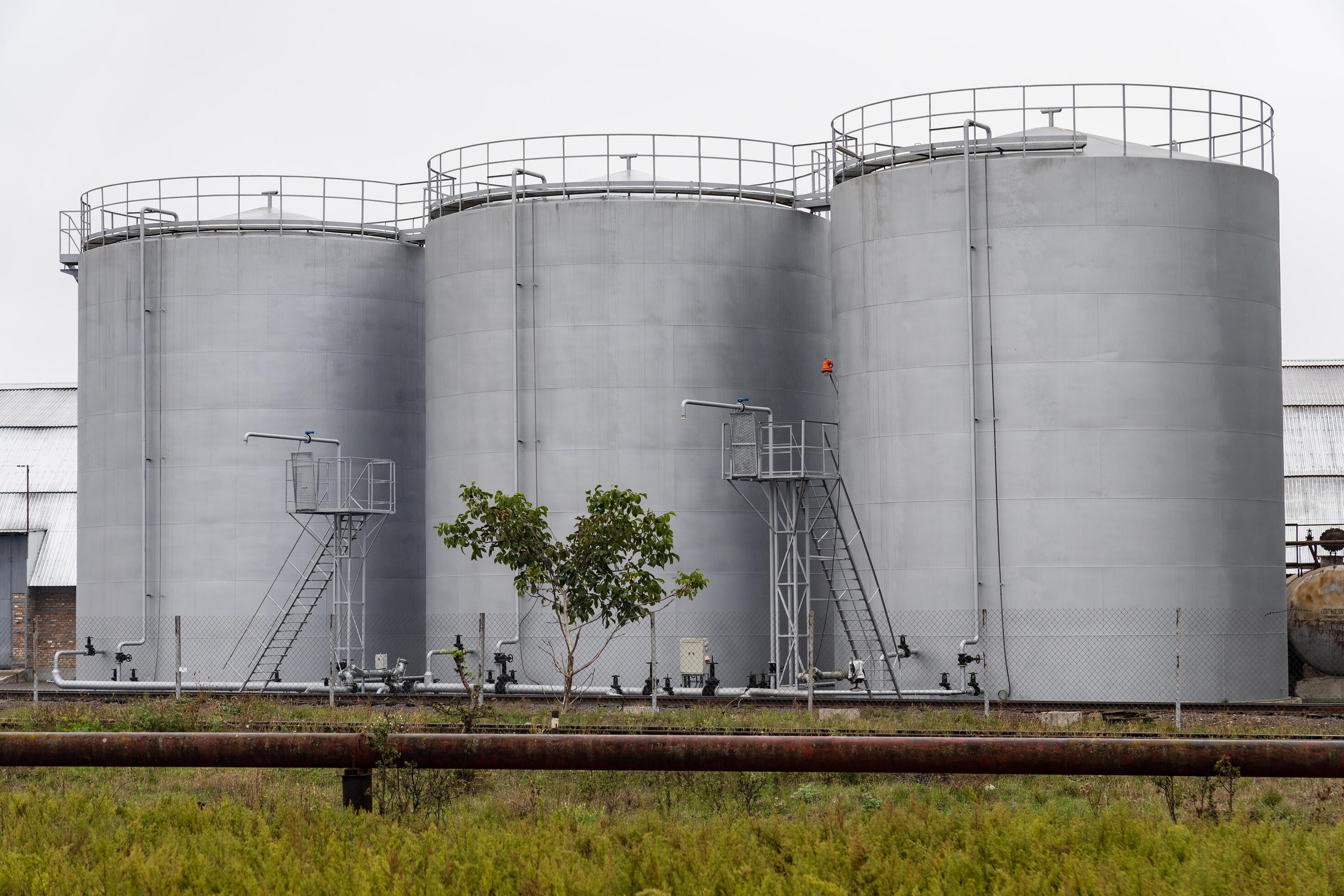 Three large fuel storage tanks stand at an industrial site, featuring ...